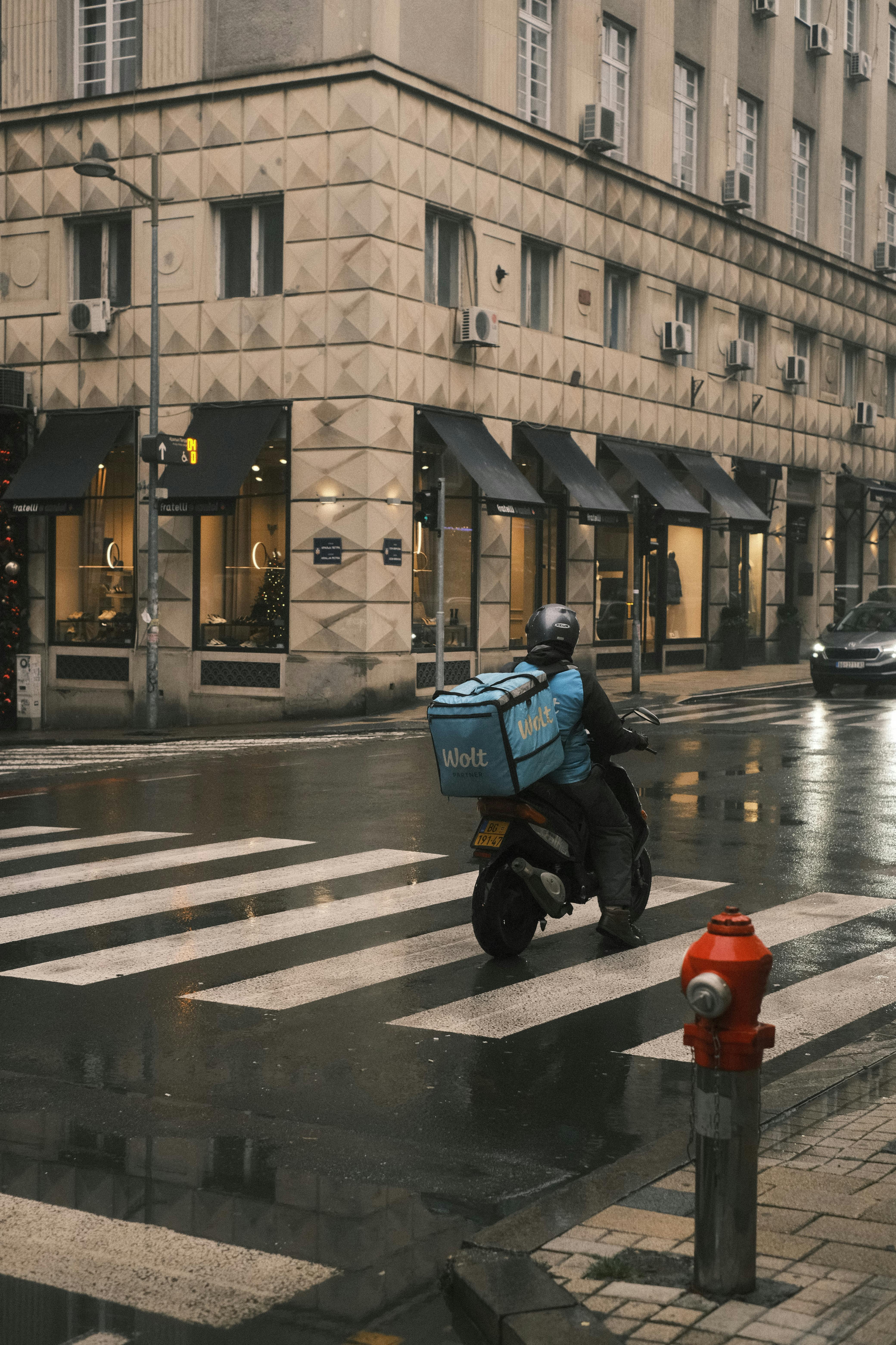 Wolt Delivery Driver on Wet Street · Free Stock Photo