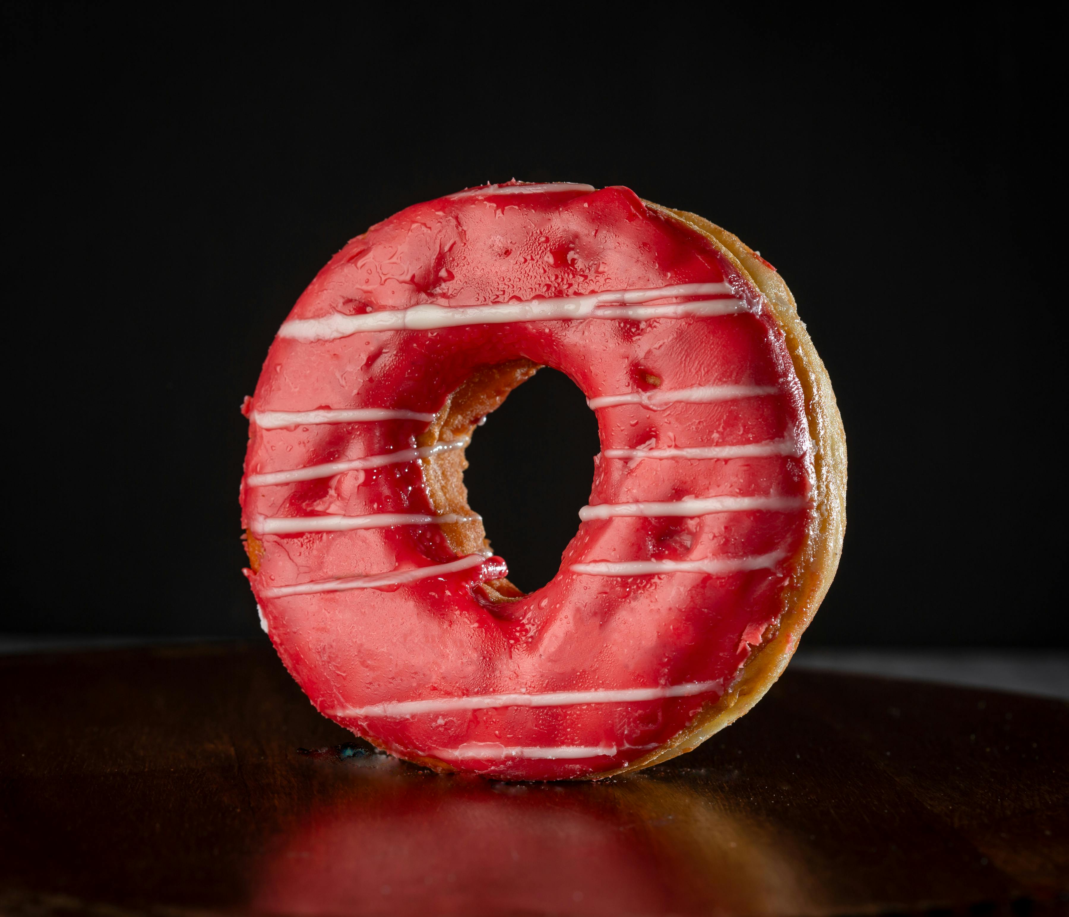 A red glazed donut with white icing · Free Stock Photo