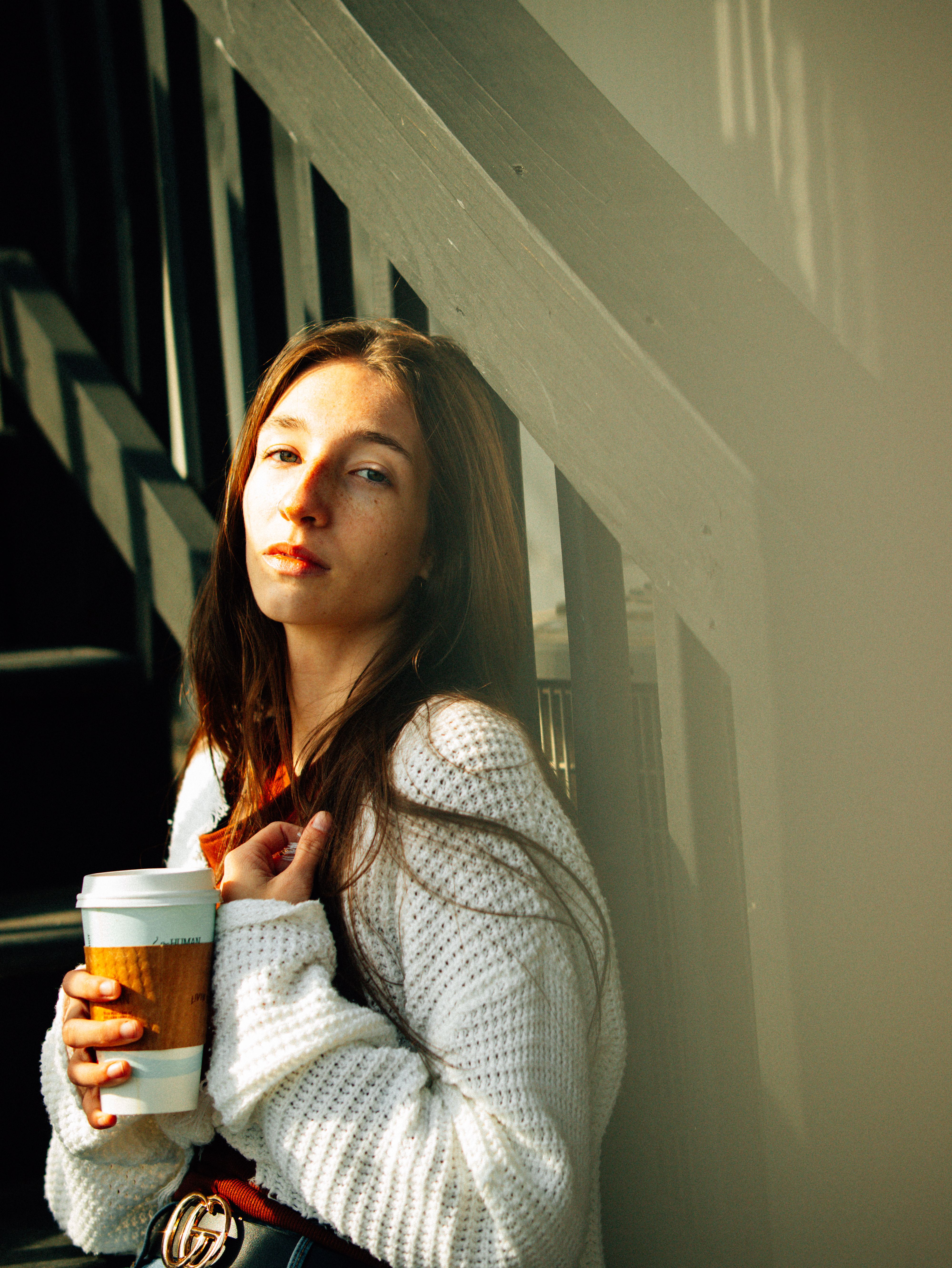 Young woman wearing white sweater drinking coffee · Free Stock Photo