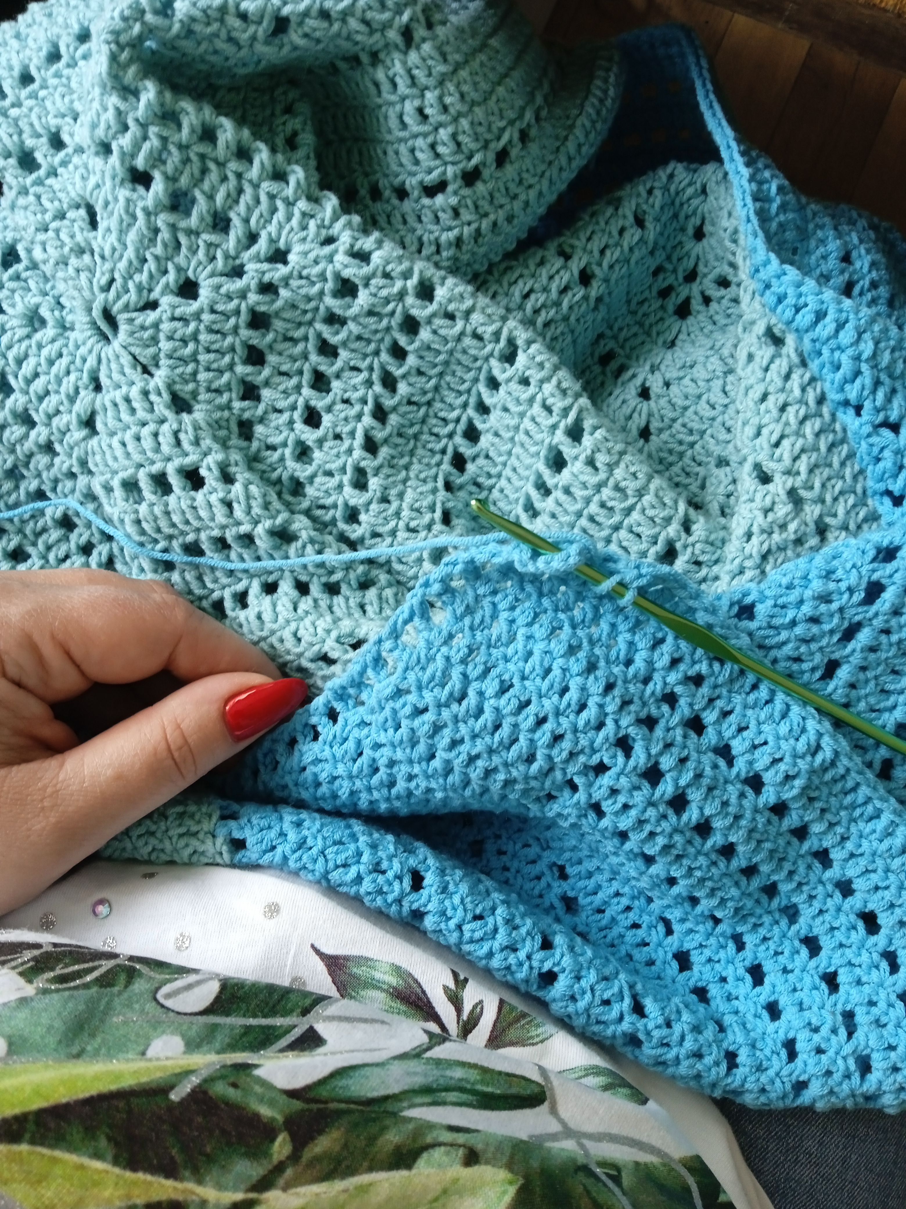 A person is holding a crochet hook and crocheting a blue blanket · Free ...