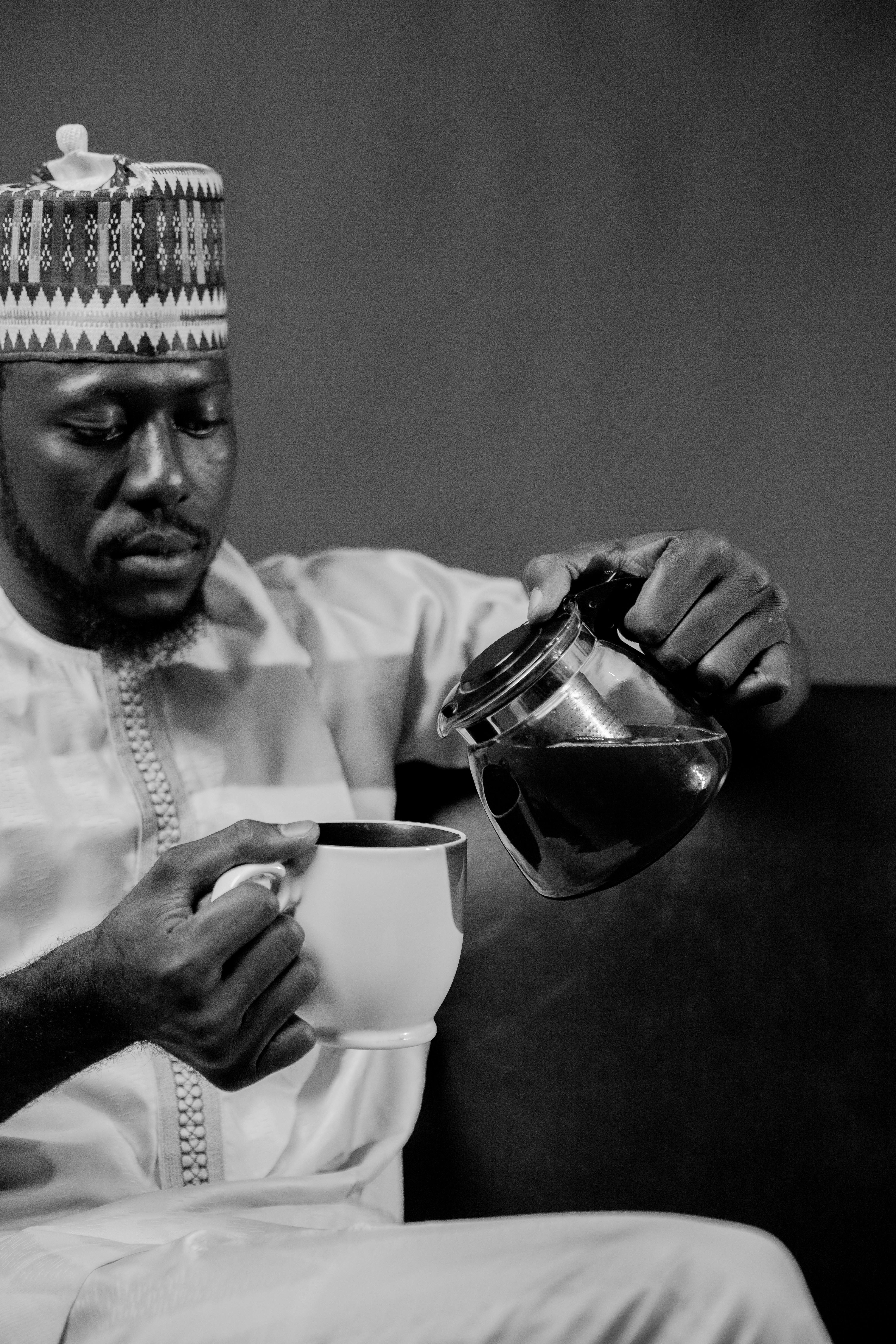Man Wearing Traditional Hat Filling Cup with Tea in Black and White ...