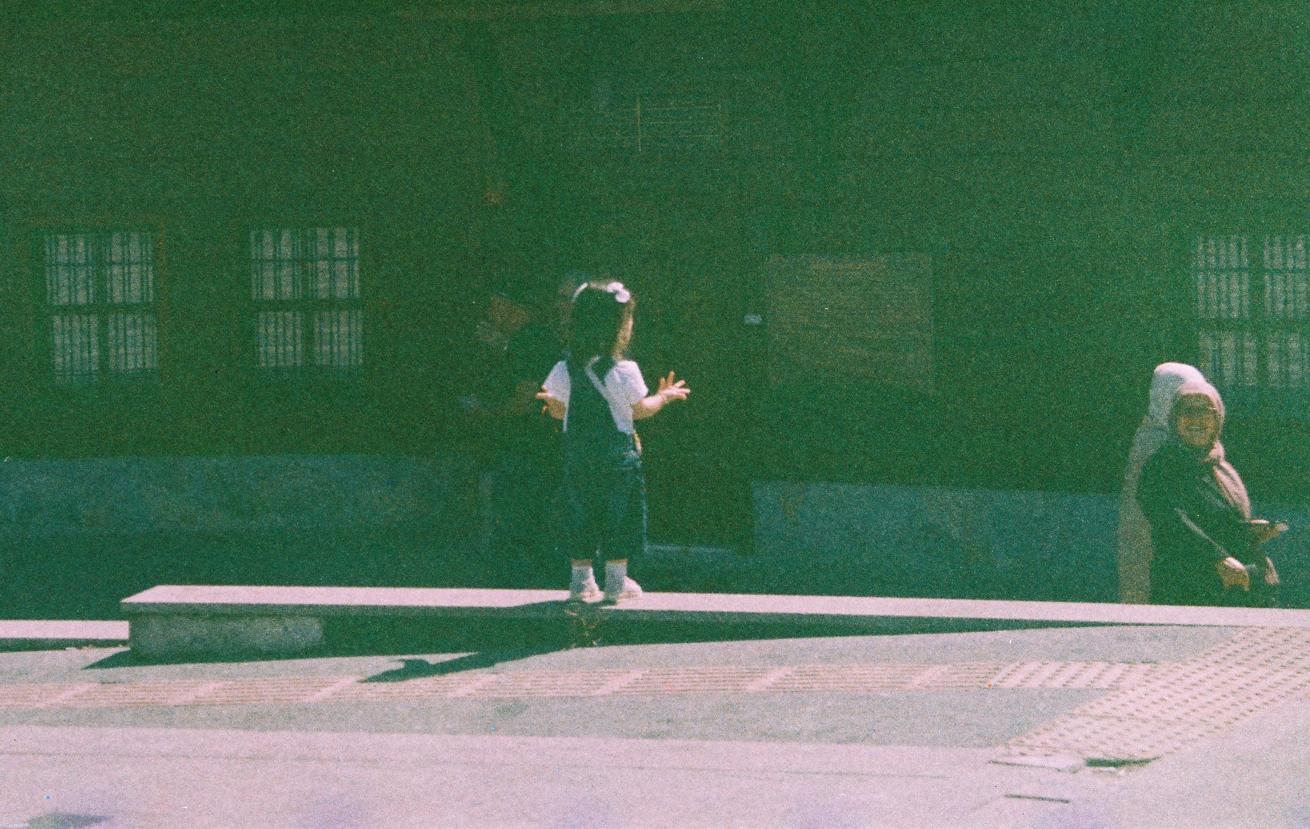 Girl Standing on Wall and People Walking near · Free Stock Photo