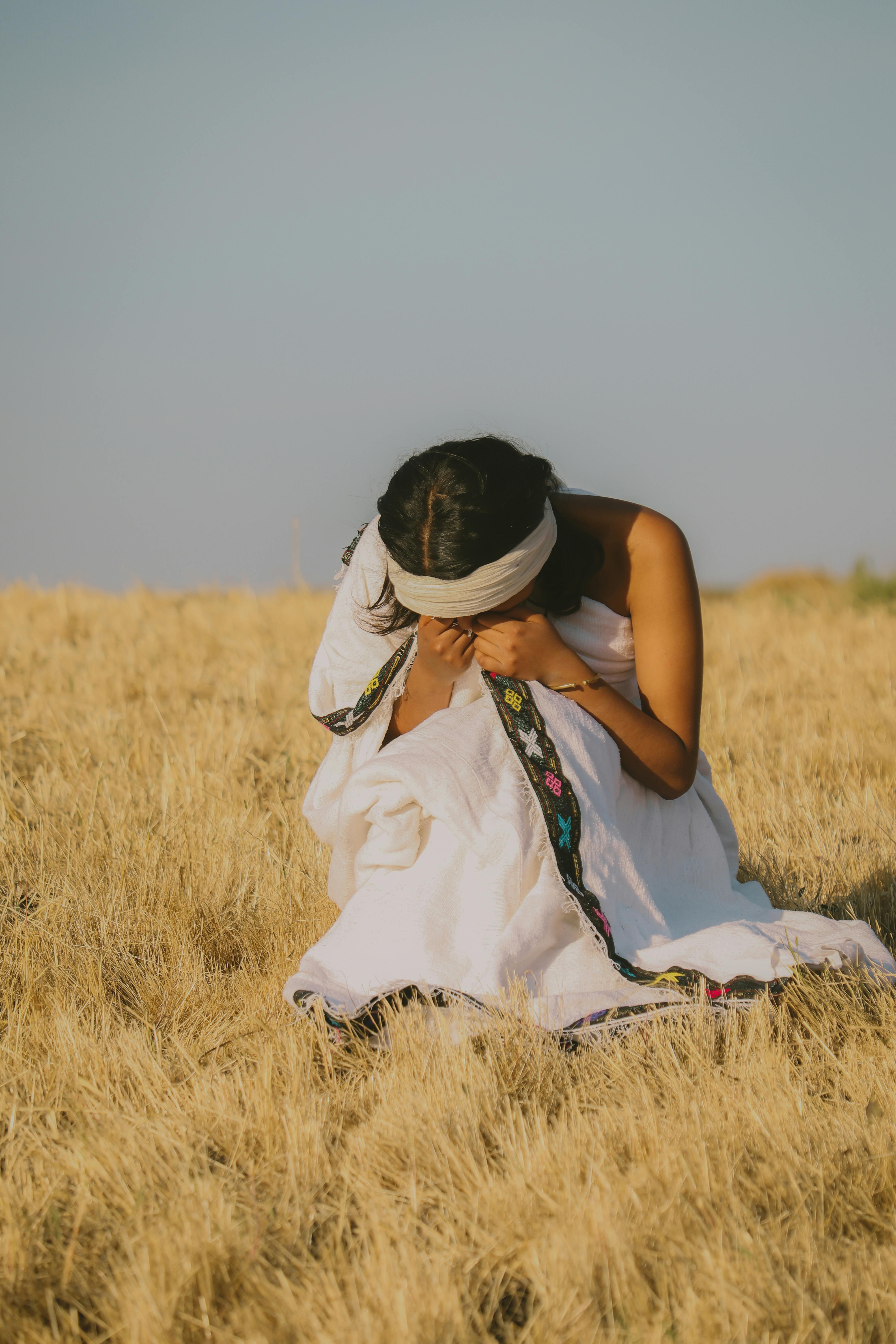 Curled Up Woman in the Field Hiding Her Face · Free Stock Photo