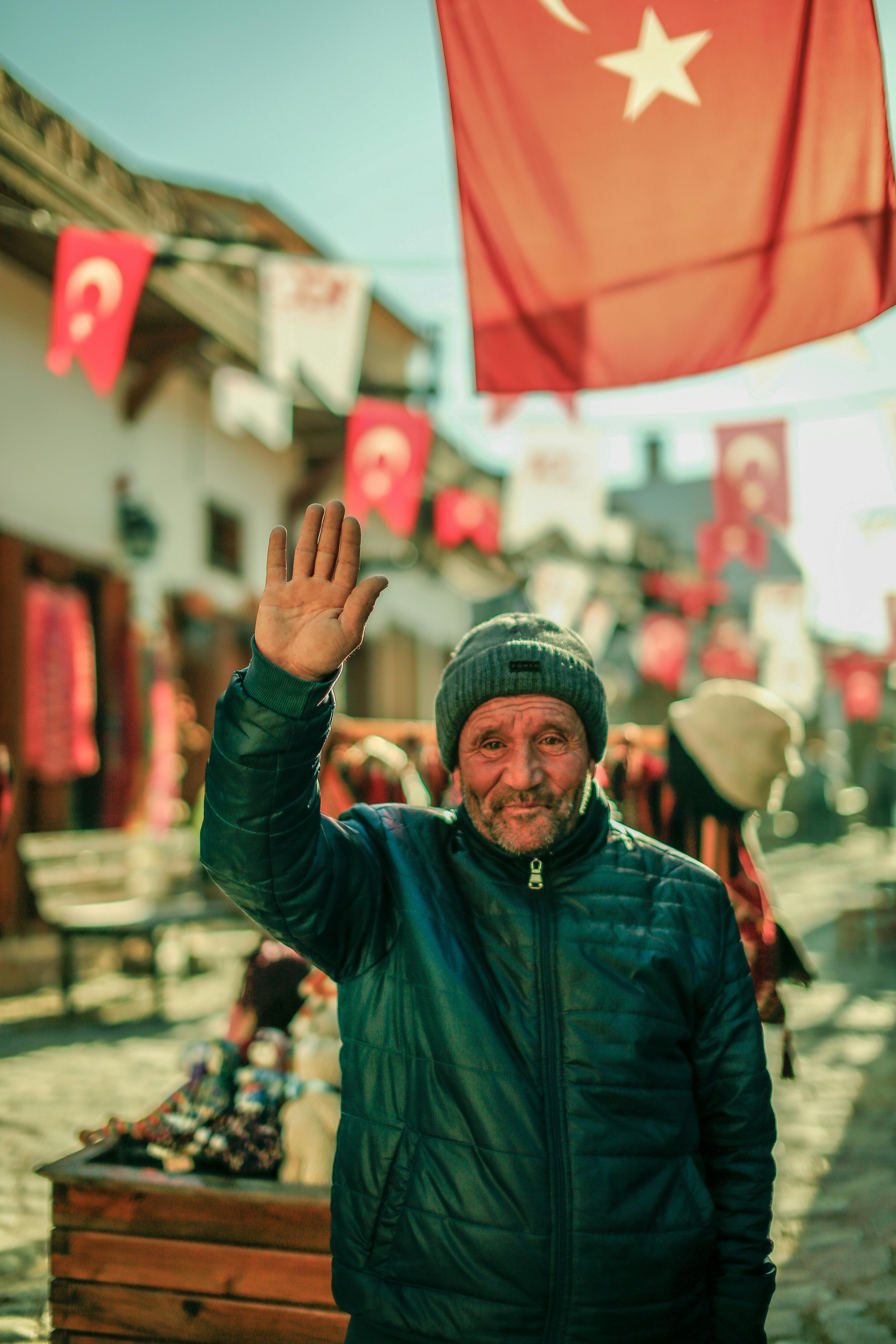 A man waving at the camera in front of a flag · Free Stock Photo
