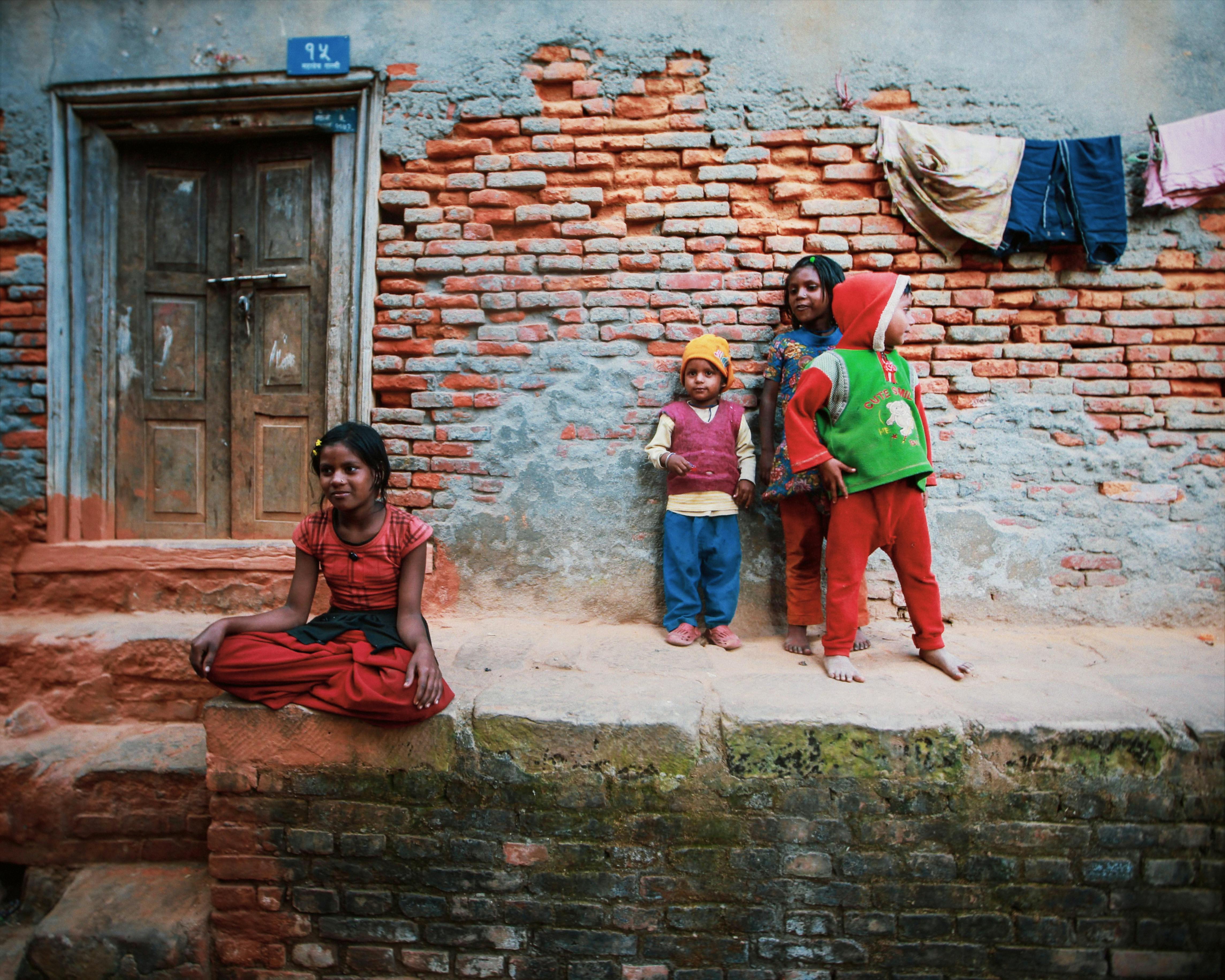 Children Playing by a Weathered Brick Building · Free Stock Photo