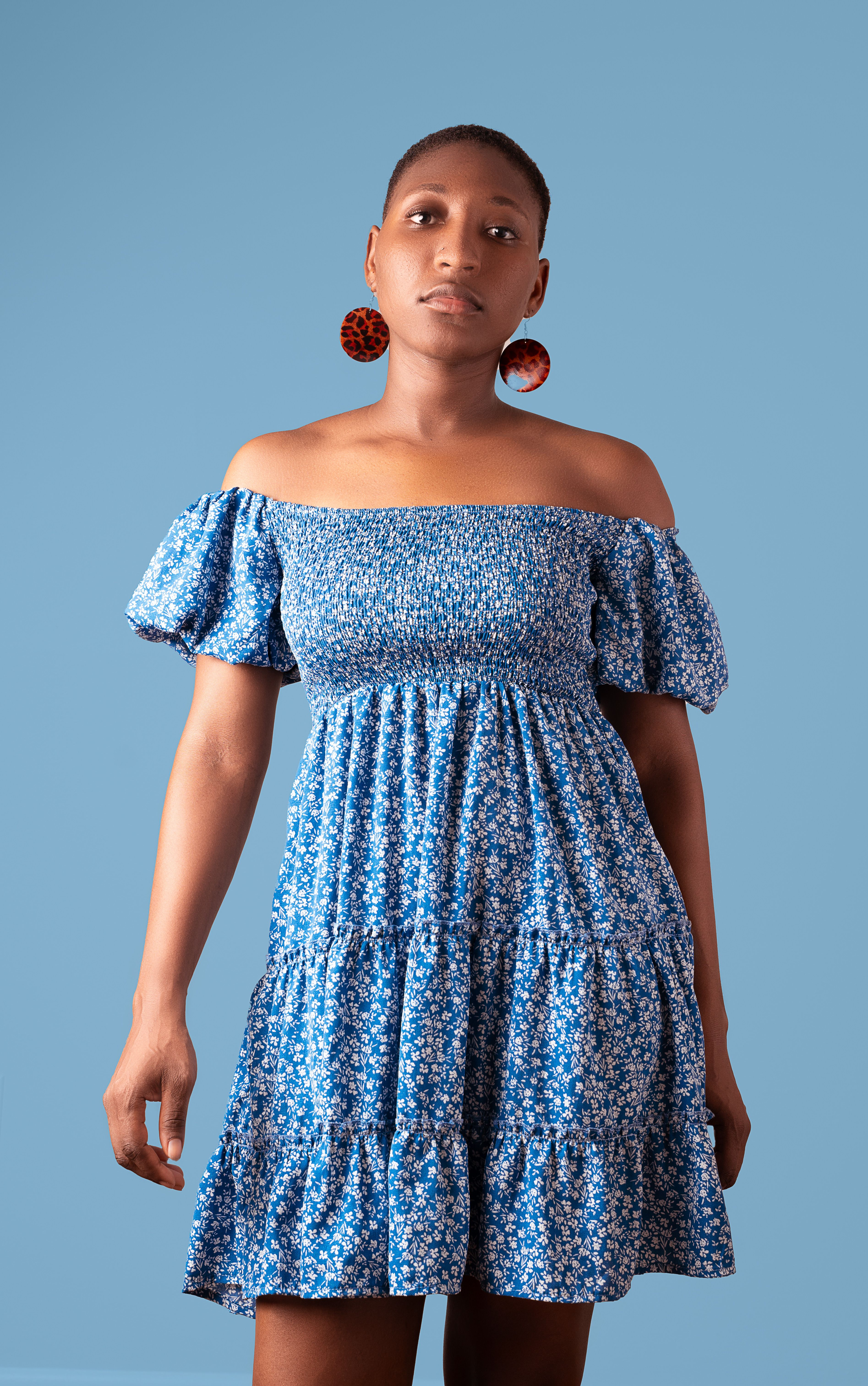 Woman in a Patterned Sundress and Earrings Standing on Blue Background ...