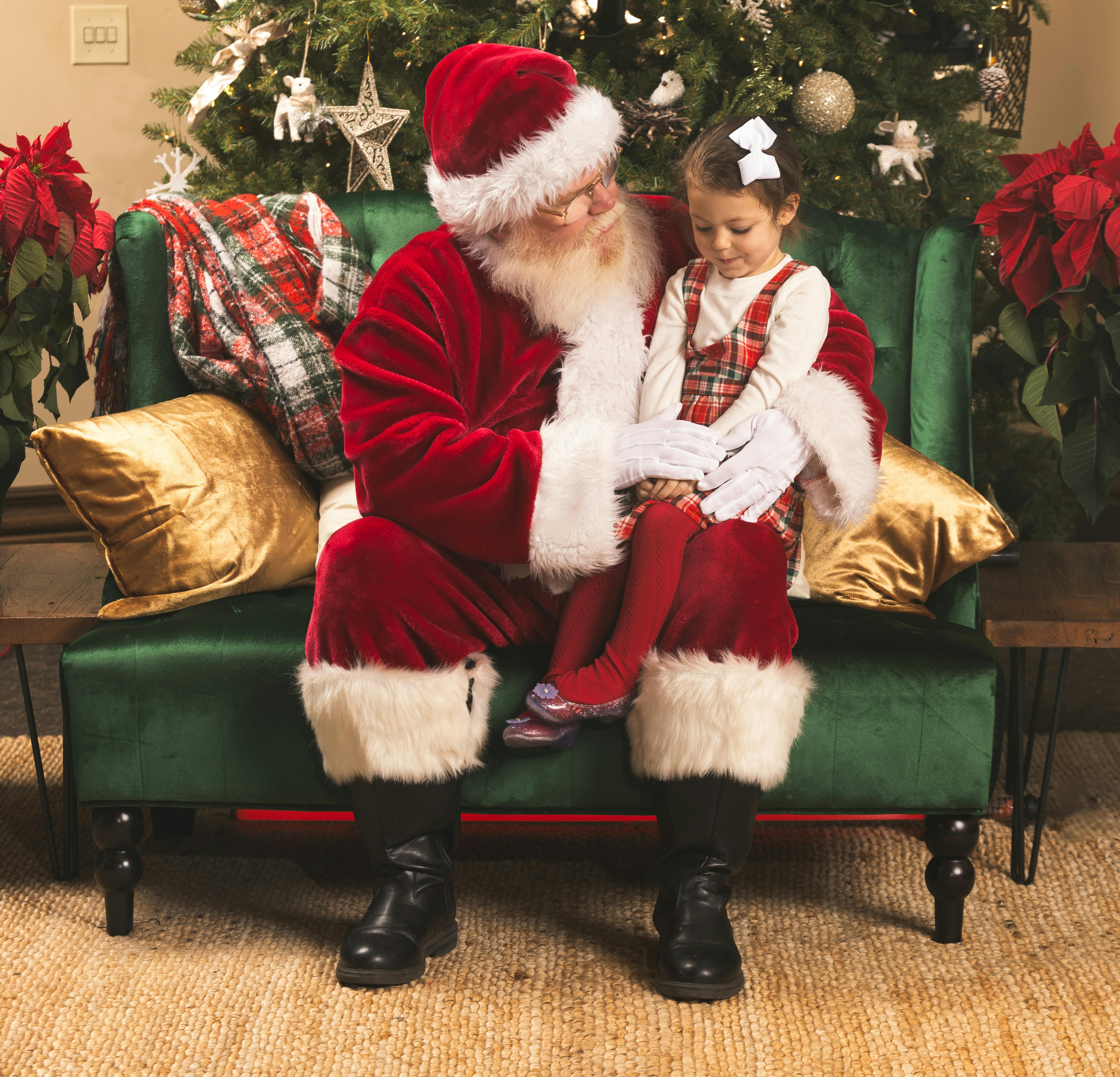 A Little Girl Sitting on the Santa Clauses Lap by the Christmas Tree ...