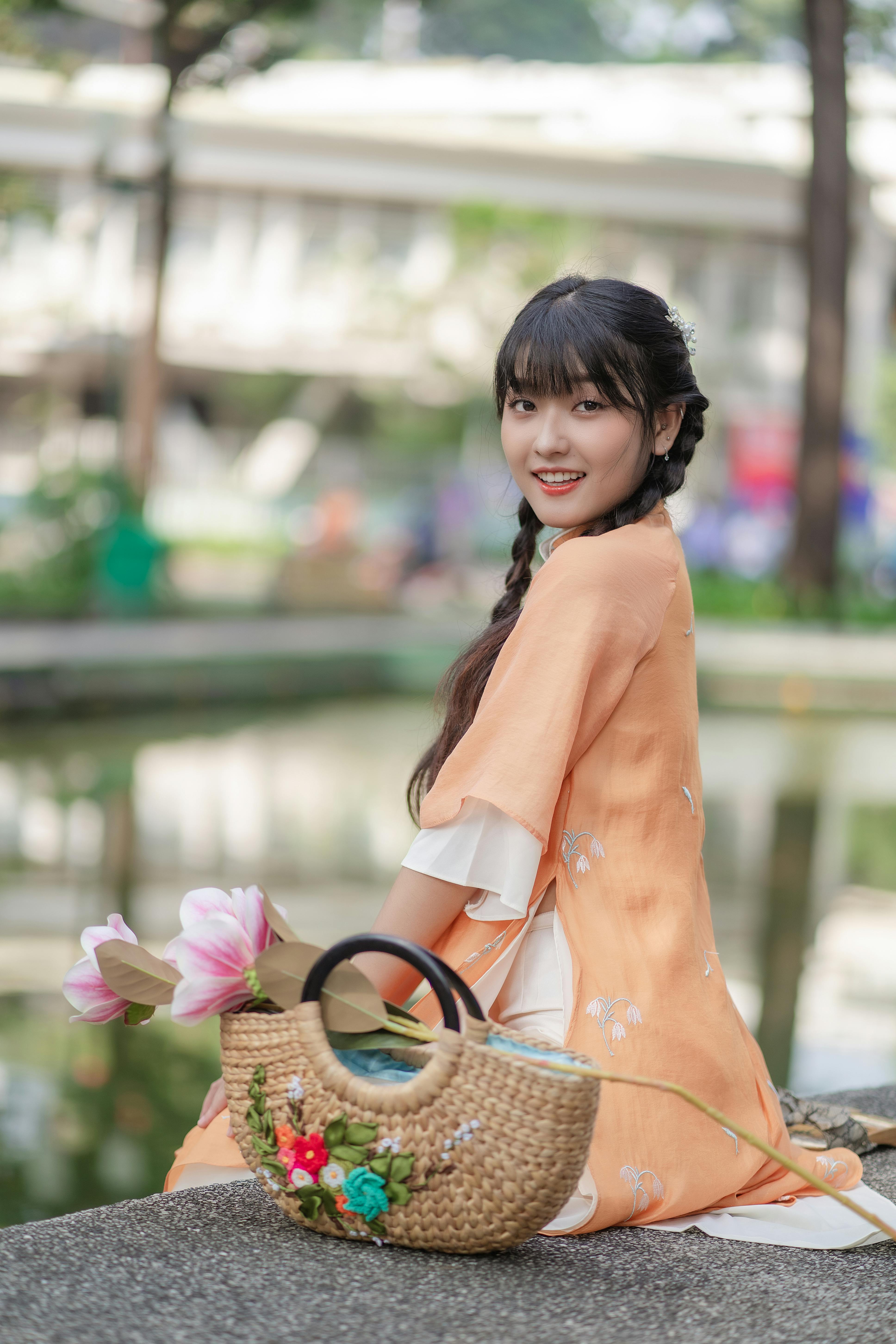 Young Model in Orange Ao Dai Tunic Sitting on the Riverbank · Free ...