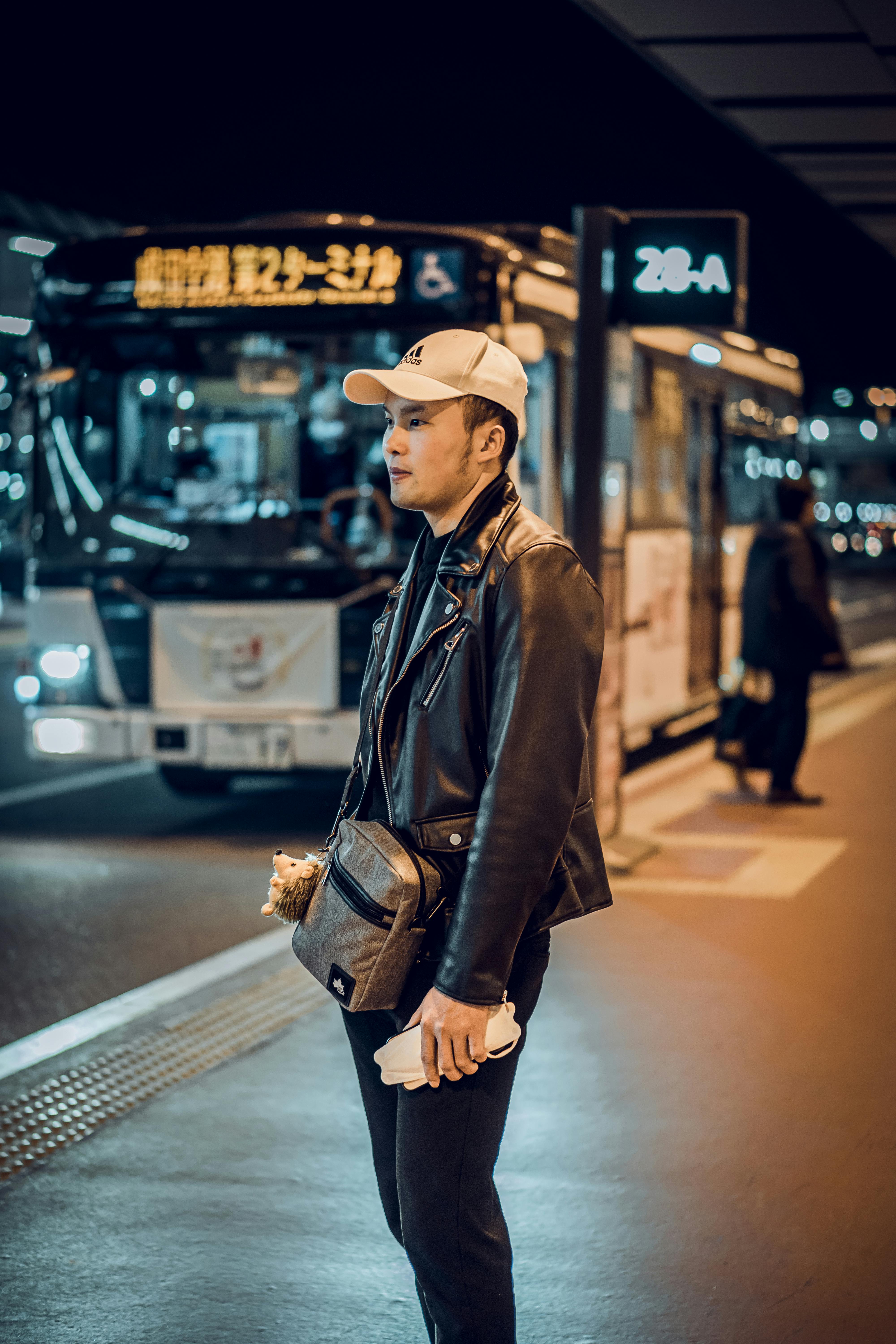 Man Standing at a Bus Stop in a City at Dusk · Free Stock Photo