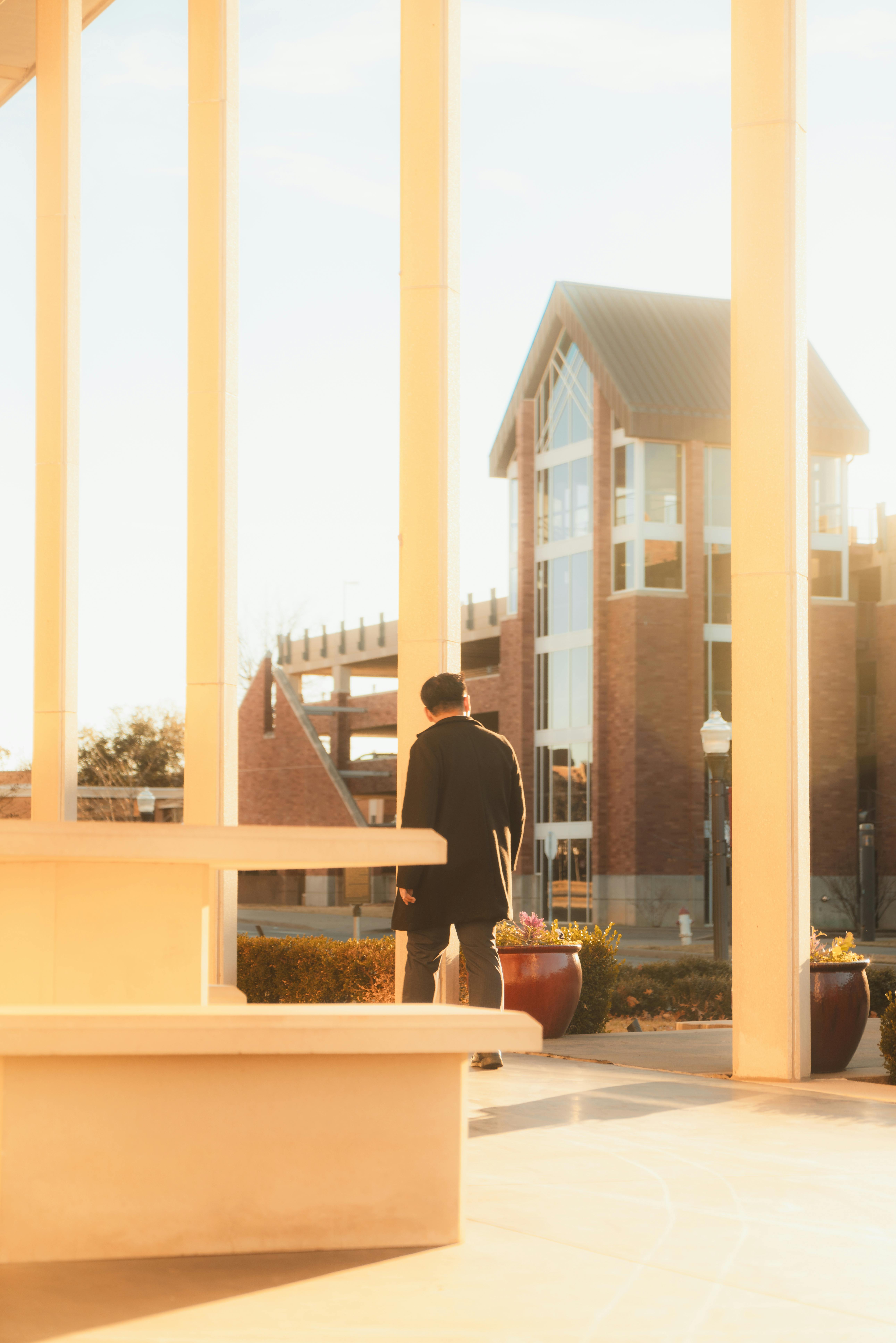 Man Walking on University Campus in Sunlight · Free Stock Photo