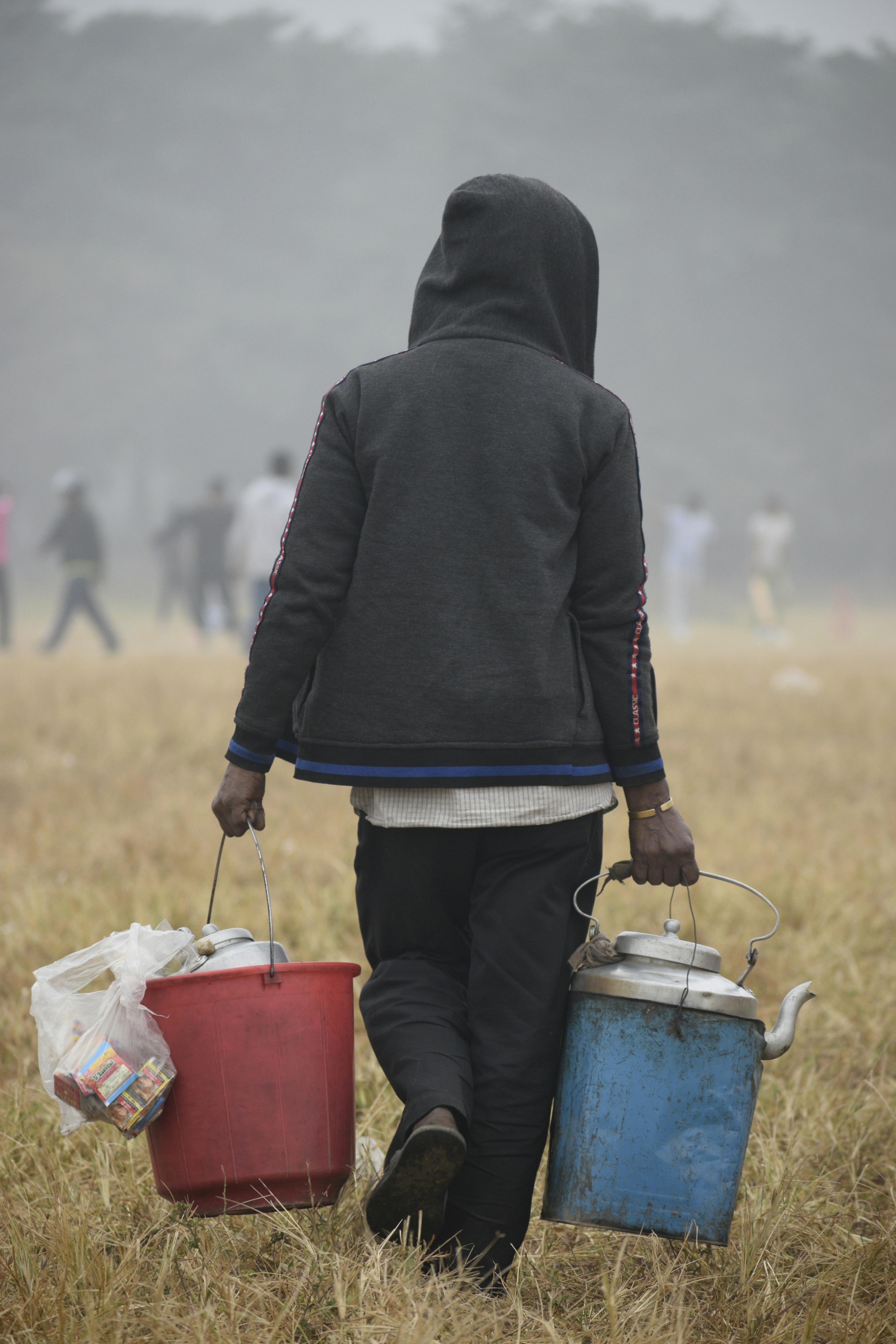 Man Carrying Bucket on Lakeshore · Free Stock Photo