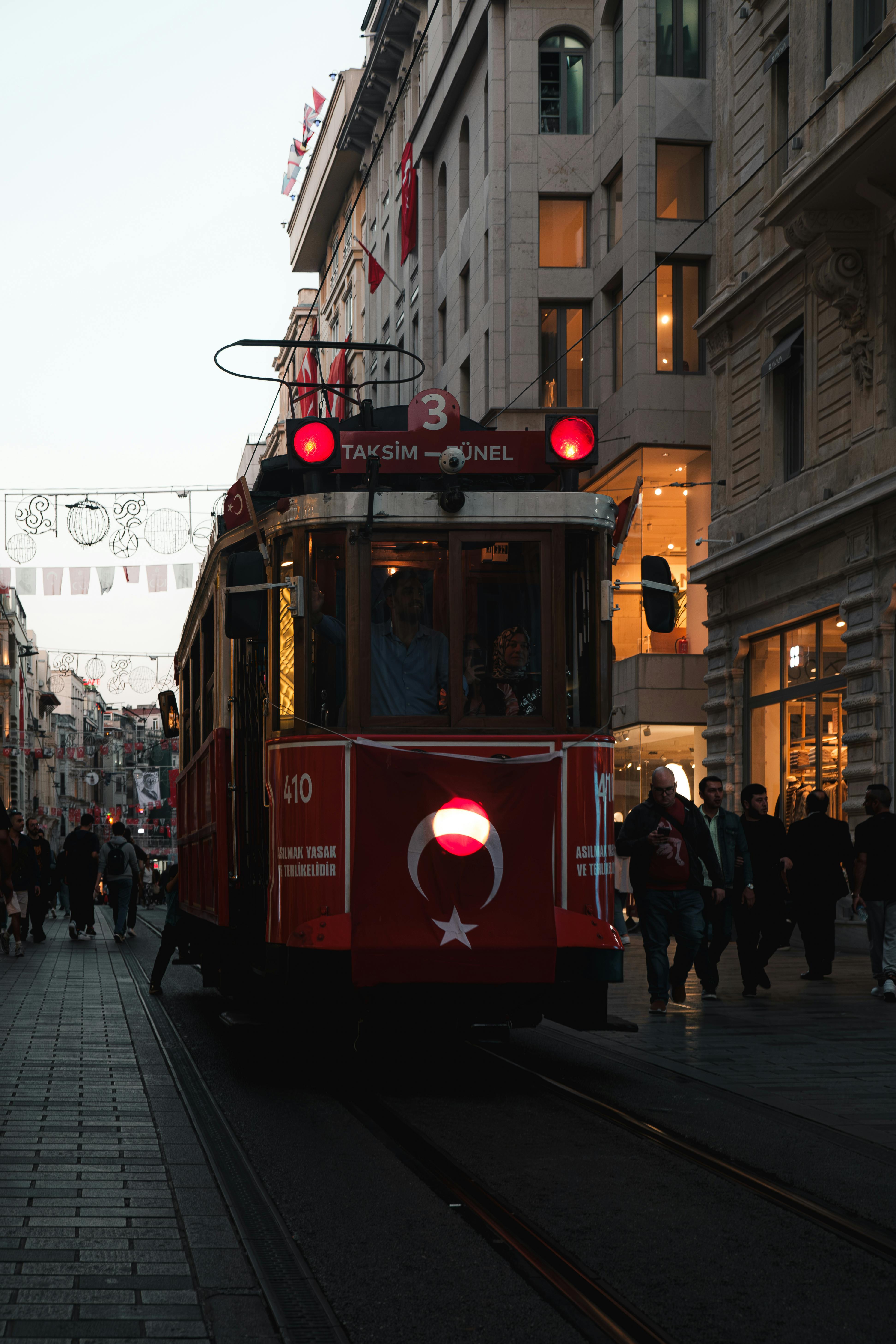 A red trolley train is traveling down a city street · Free Stock Photo