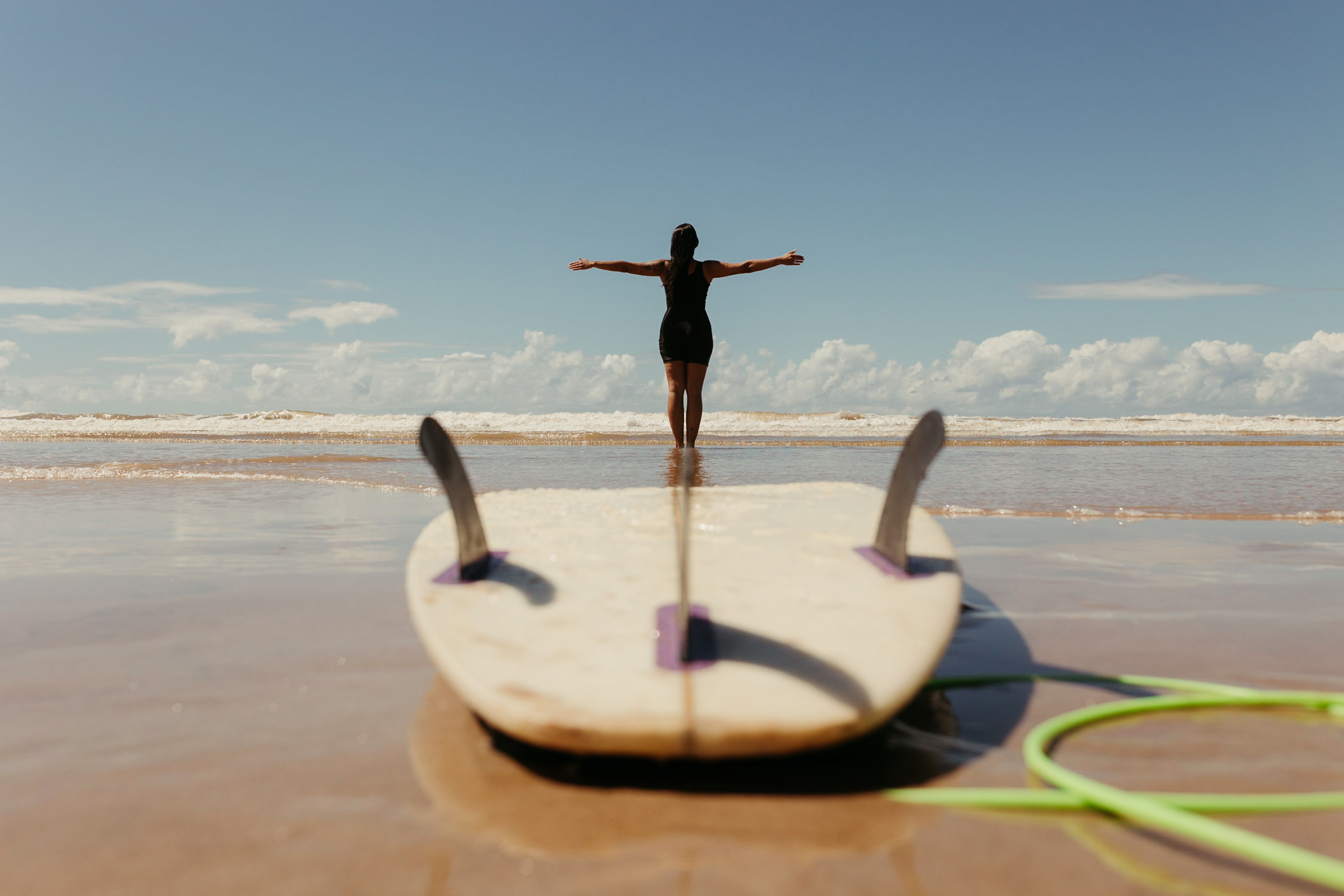 Surfer with Arms Outstretched Standing on the Beach in Front of a ...