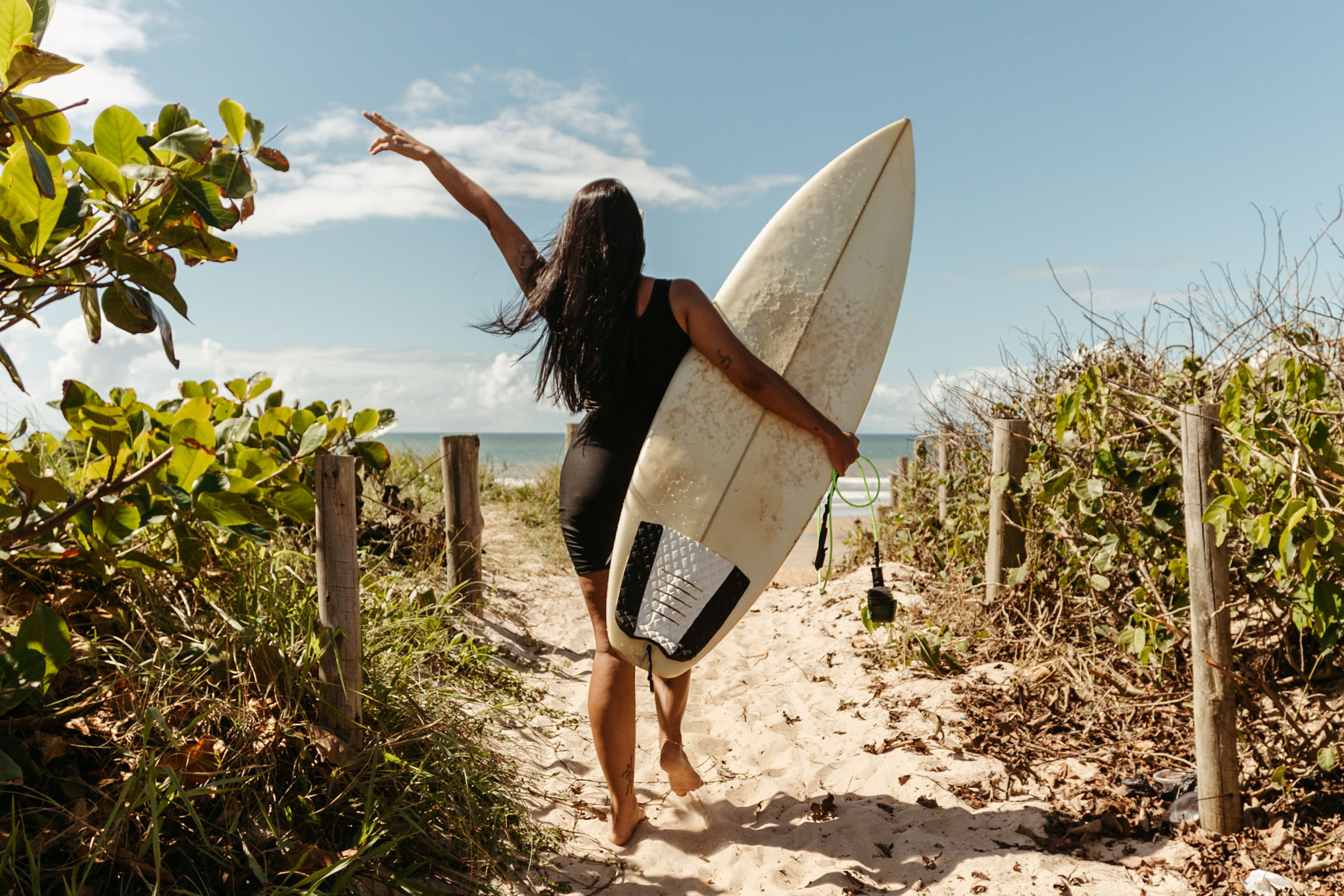 Woman Walking Down a Sandy Path to the Beach Carrying a Surfboard ...