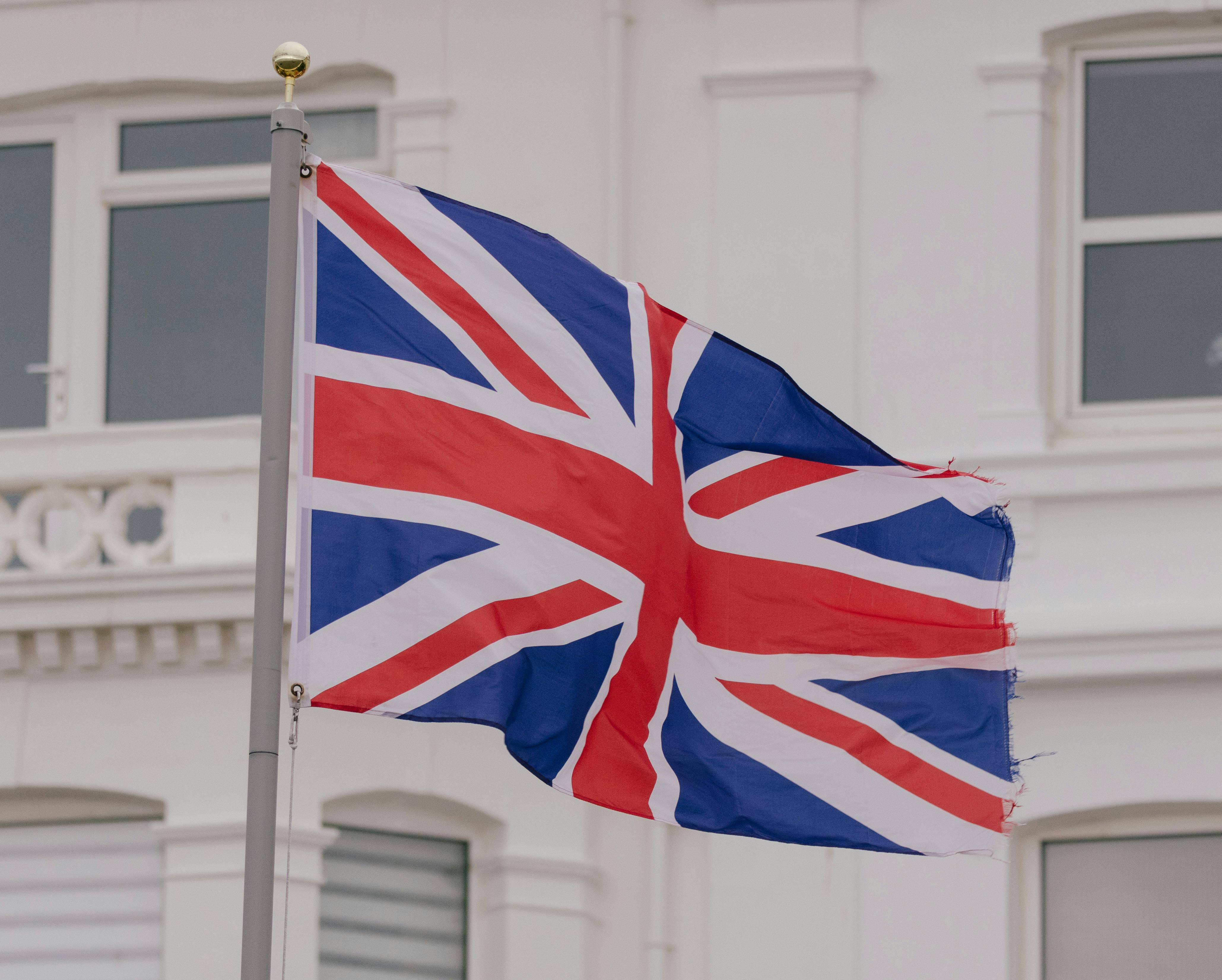 A british flag flying in front of a white building · Free Stock Photo