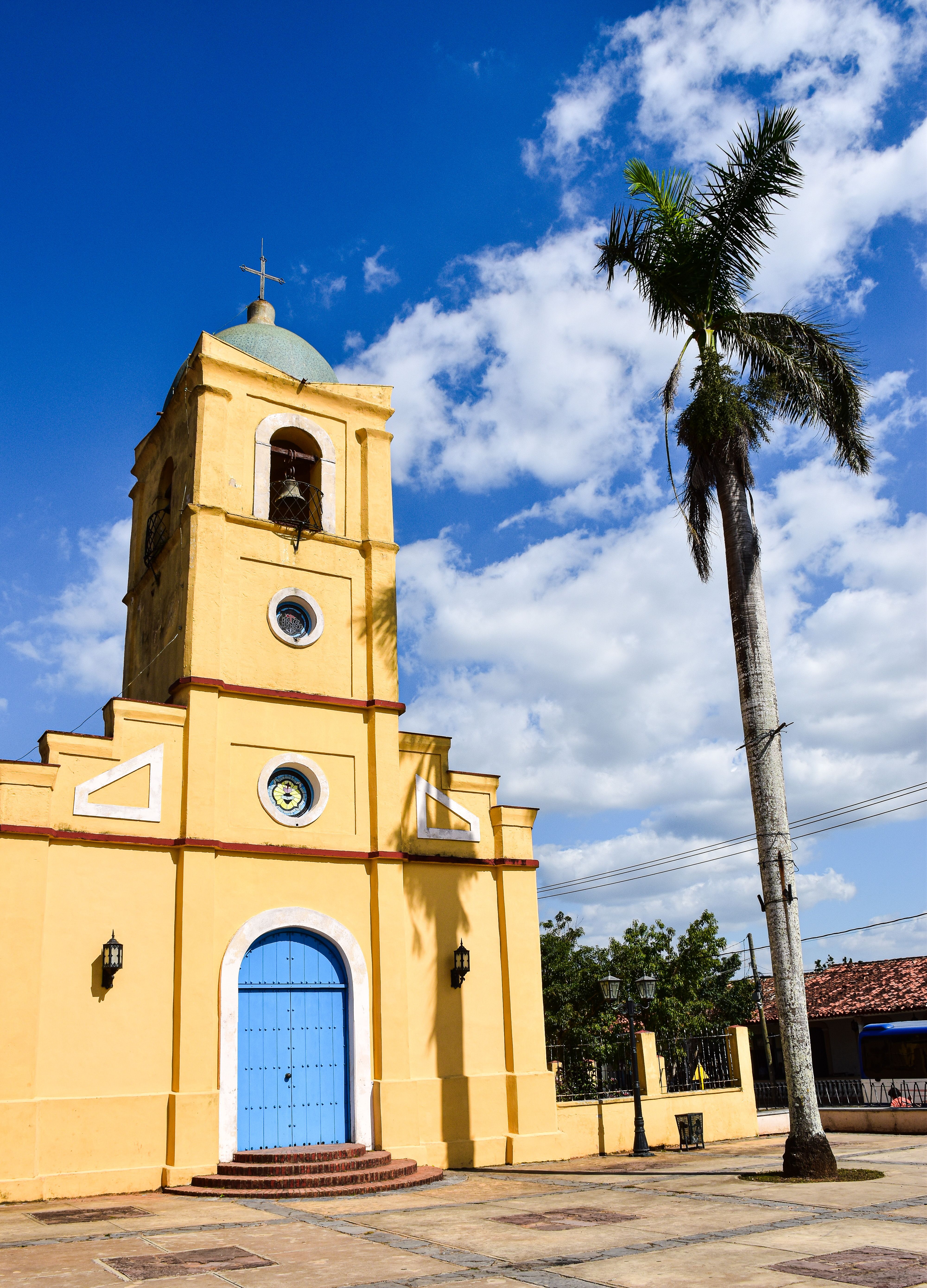 A yellow church with blue doors and palm trees · Free Stock Photo