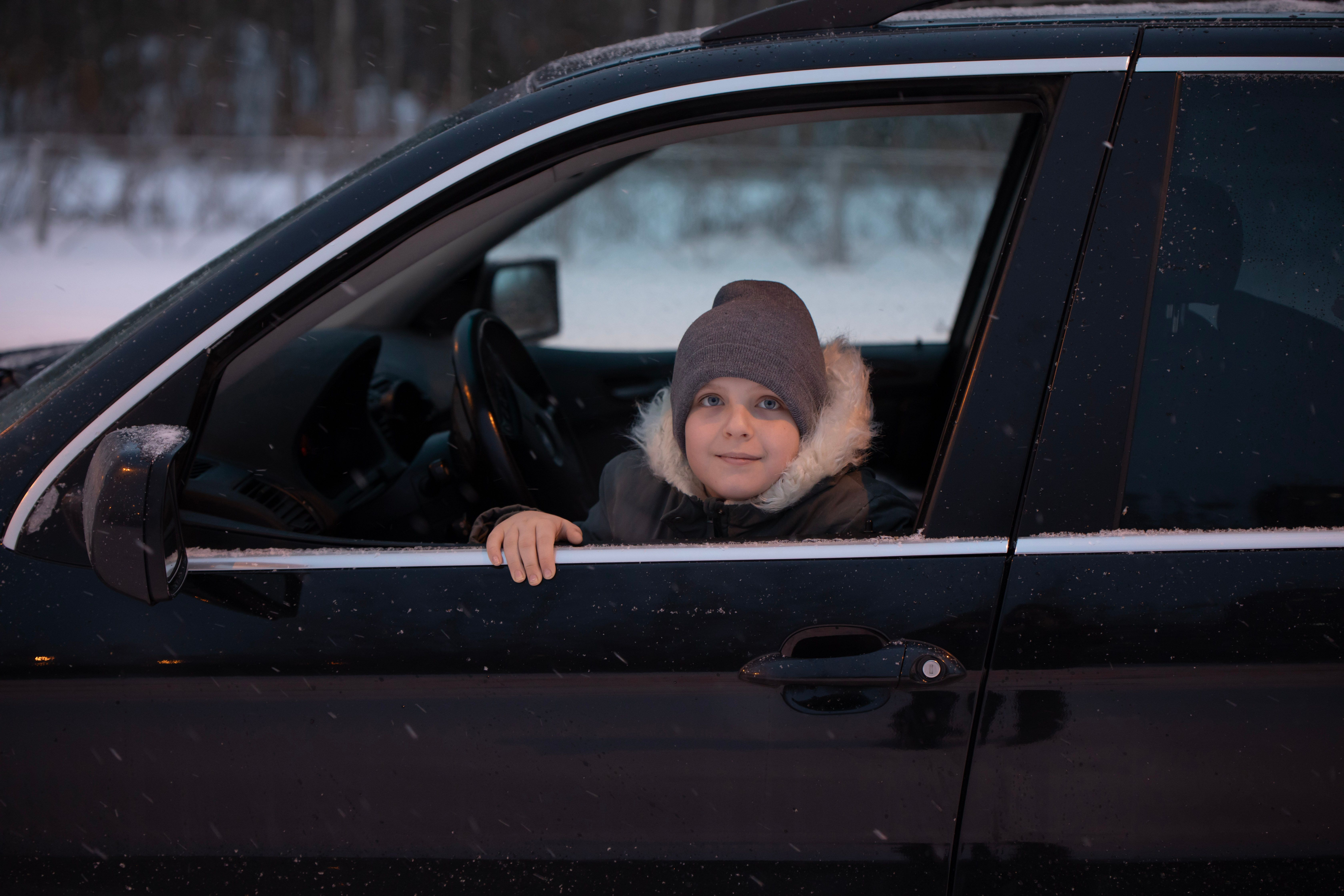 A child in a car smiling at the camera · Free Stock Photo
