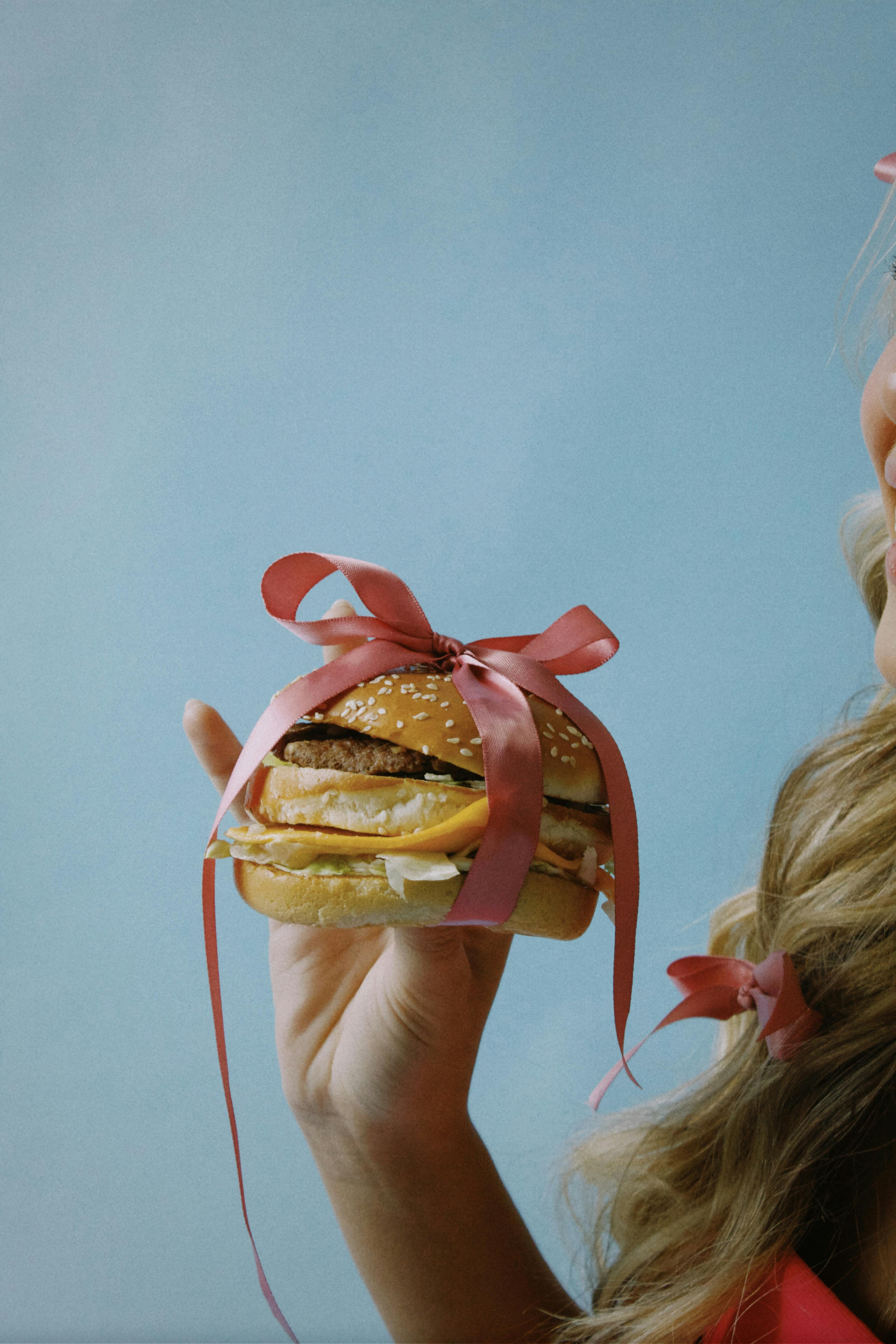 Woman Holding Burger with a Ribbon · Free Stock Photo