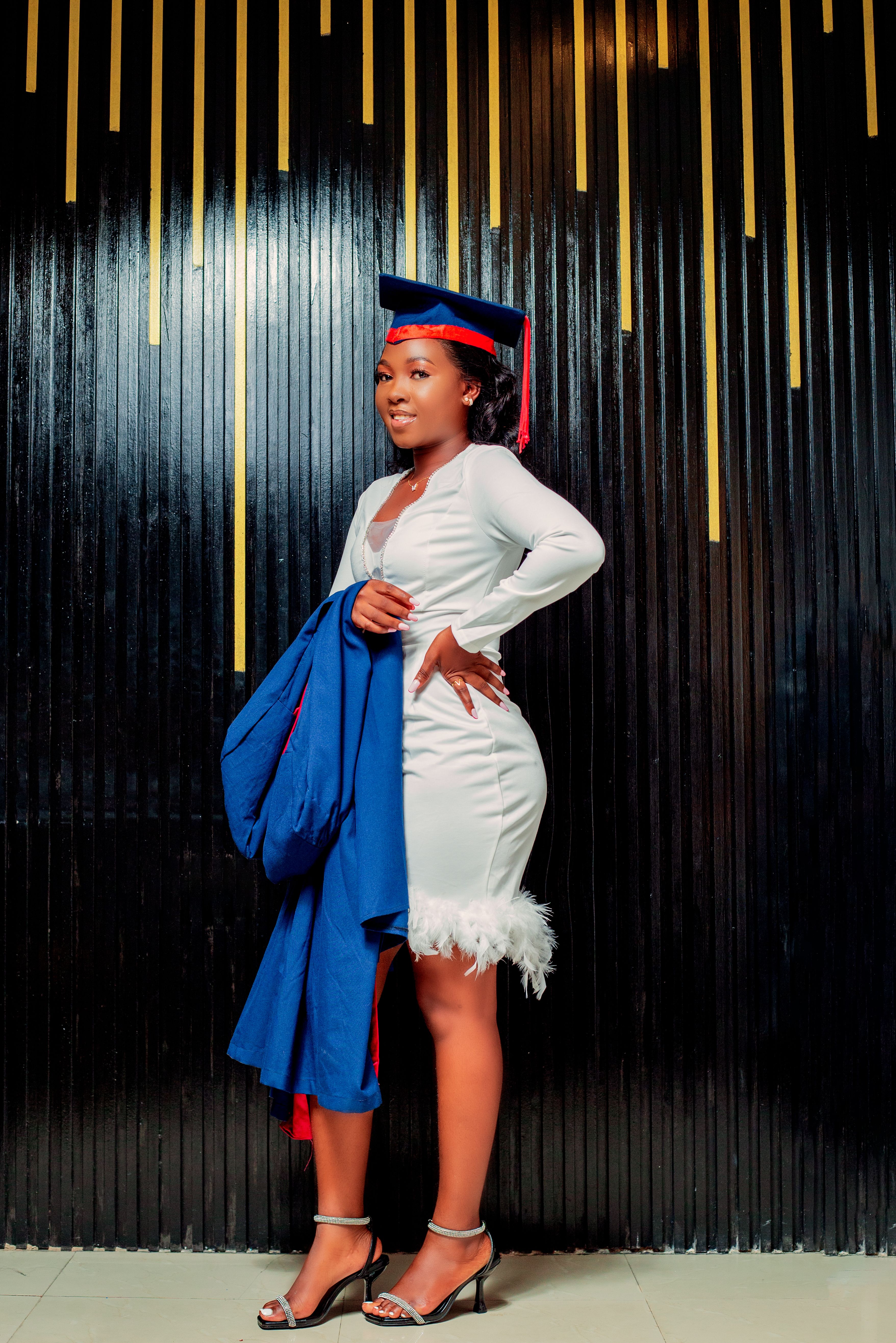 Young Student in a White Dress and Blue Mortarboard Holding Her Gown ...