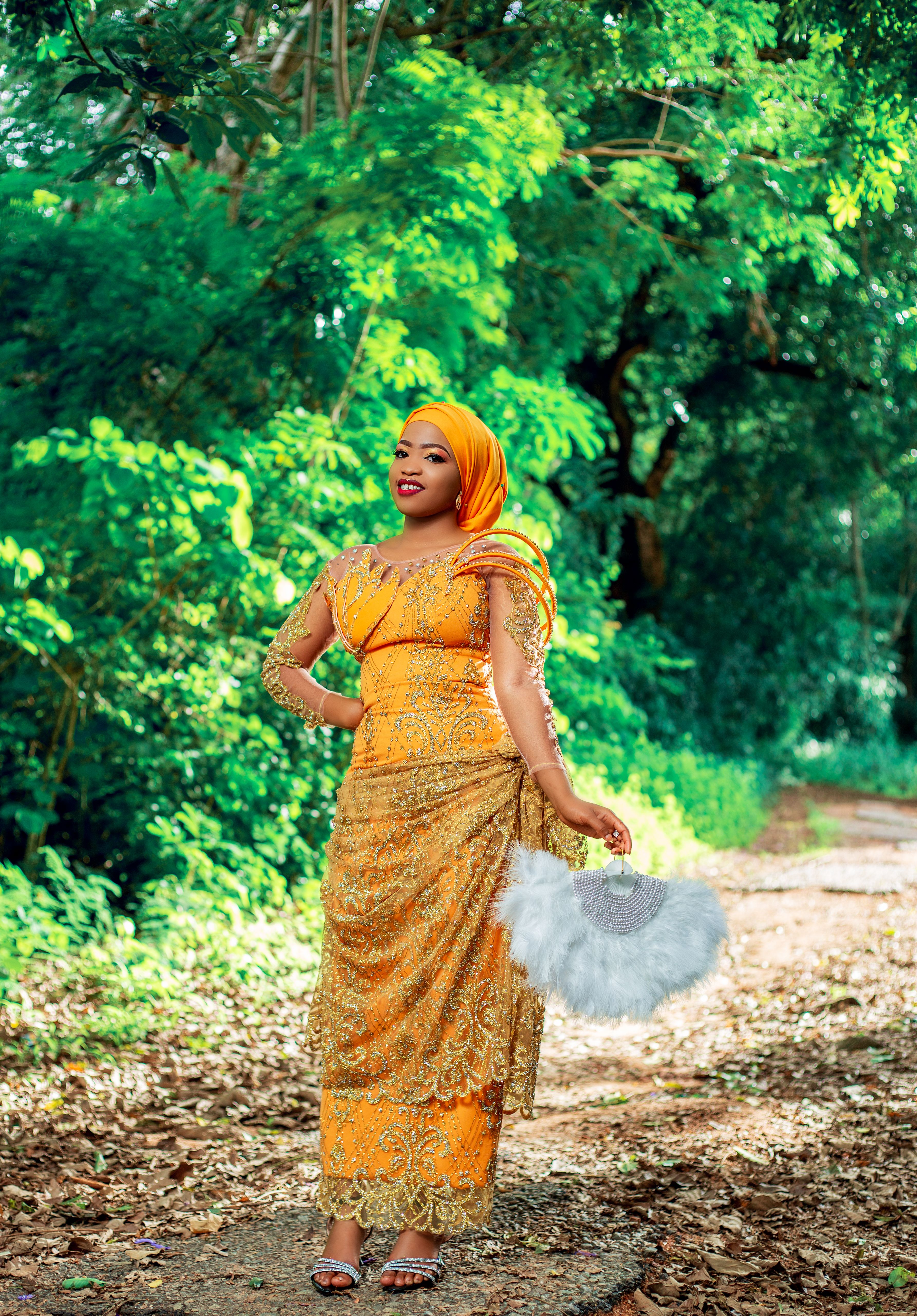 Smiling Woman in Traditional Clothing Standing on a Path Holding a Fan ...