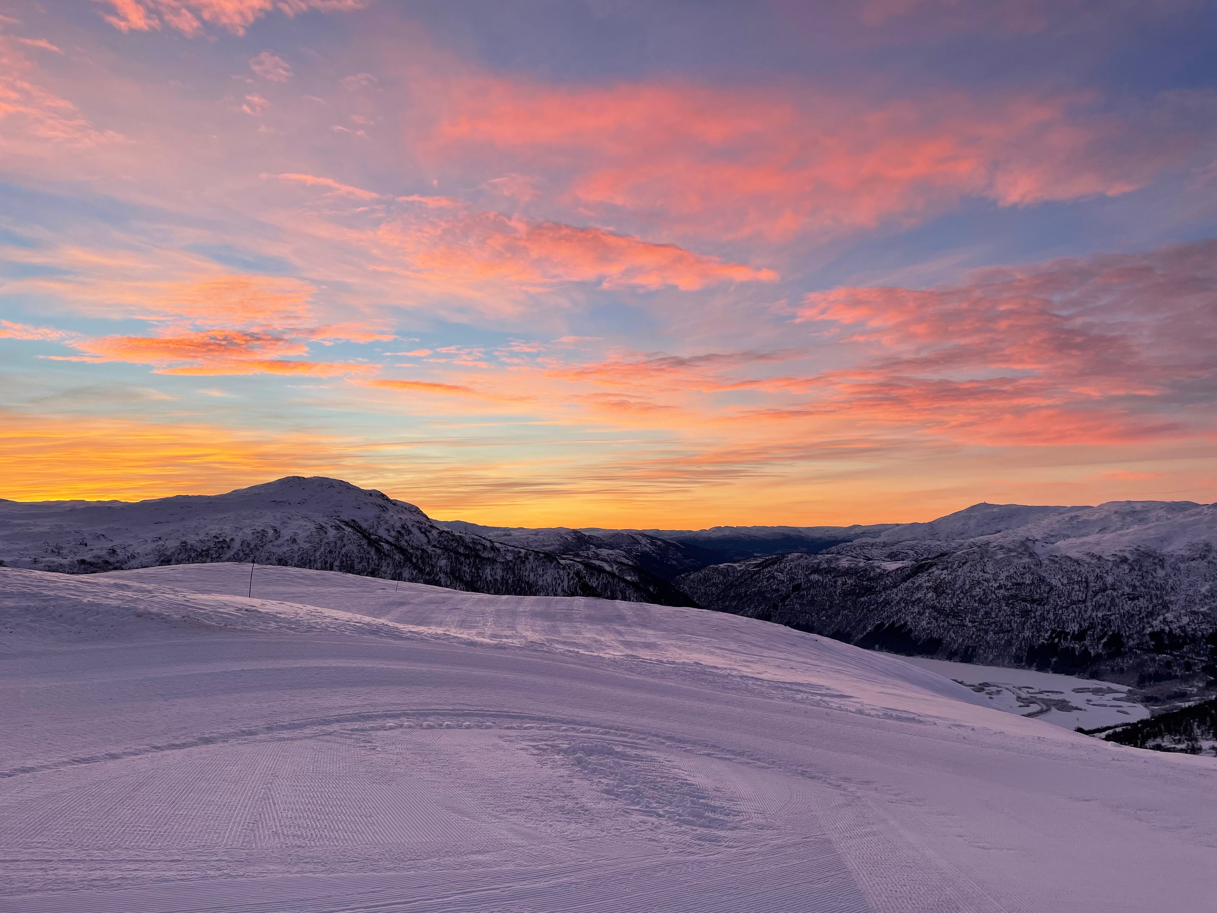 Red Illuminated Clouds over Snowed Rolling Landscape · Free Stock Photo