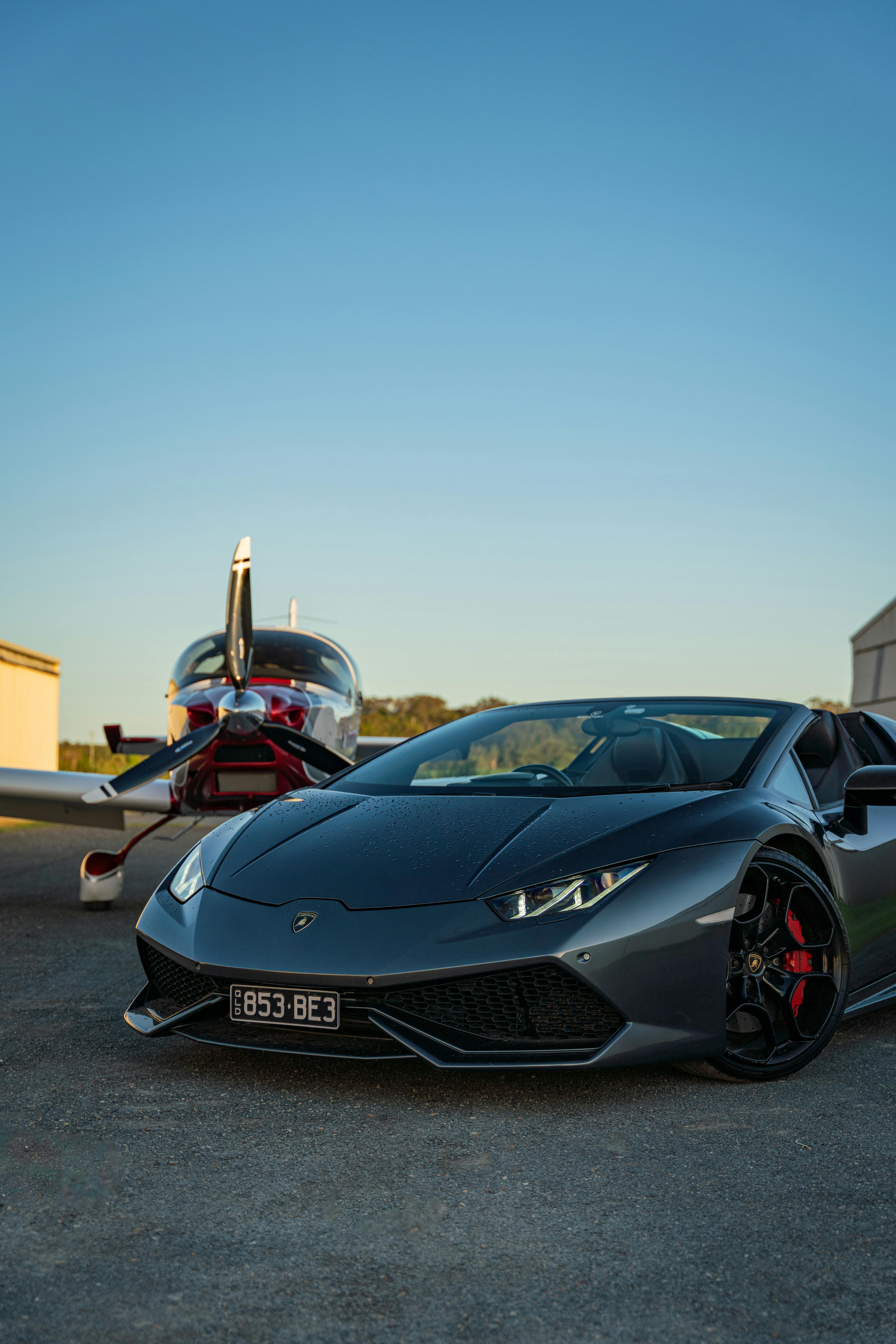 A Lamborghini Huracan Parked next to a Plane · Free Stock Photo