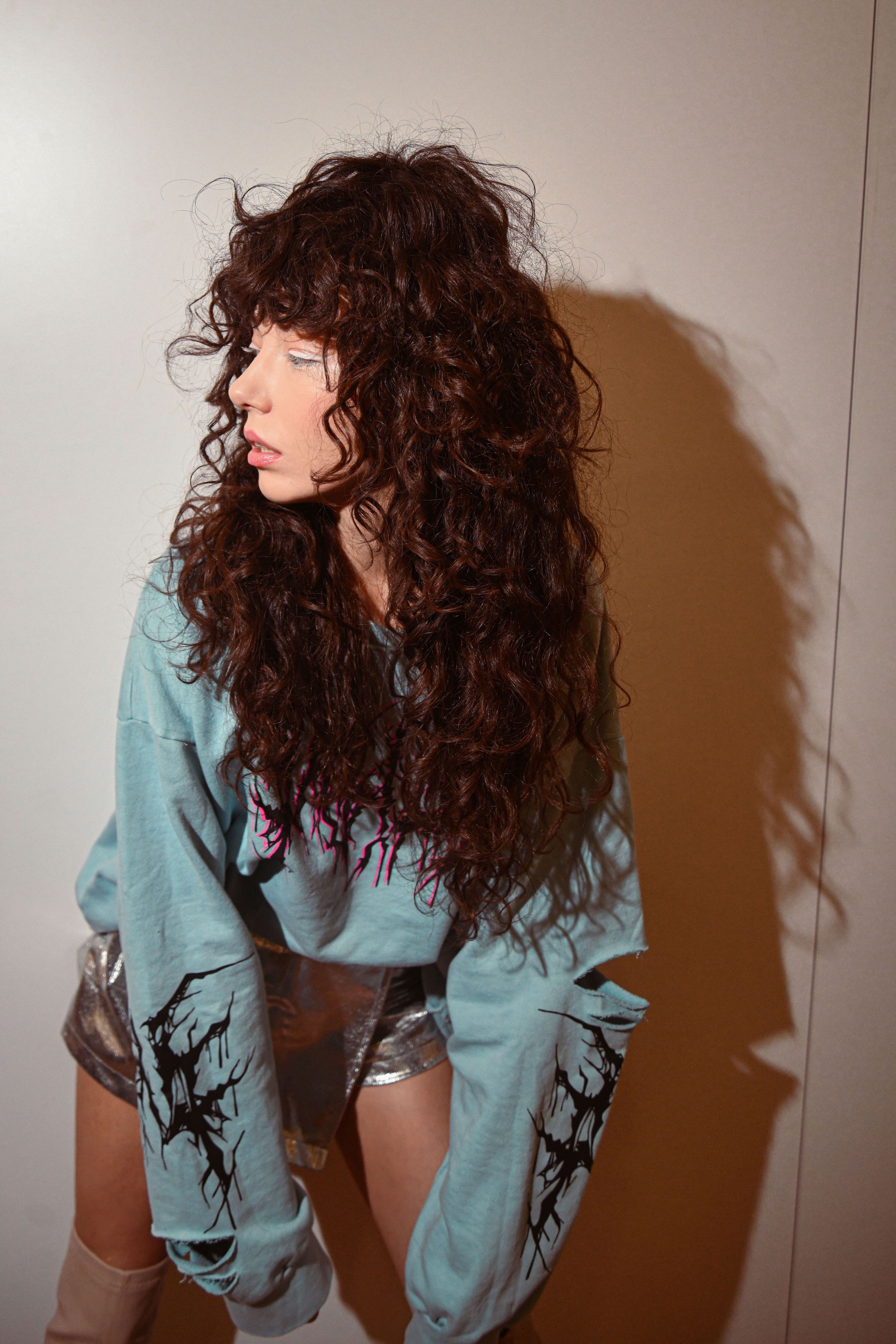 Young Woman with Curly Hair Wearing a Trendy Outfit Standing against a ...