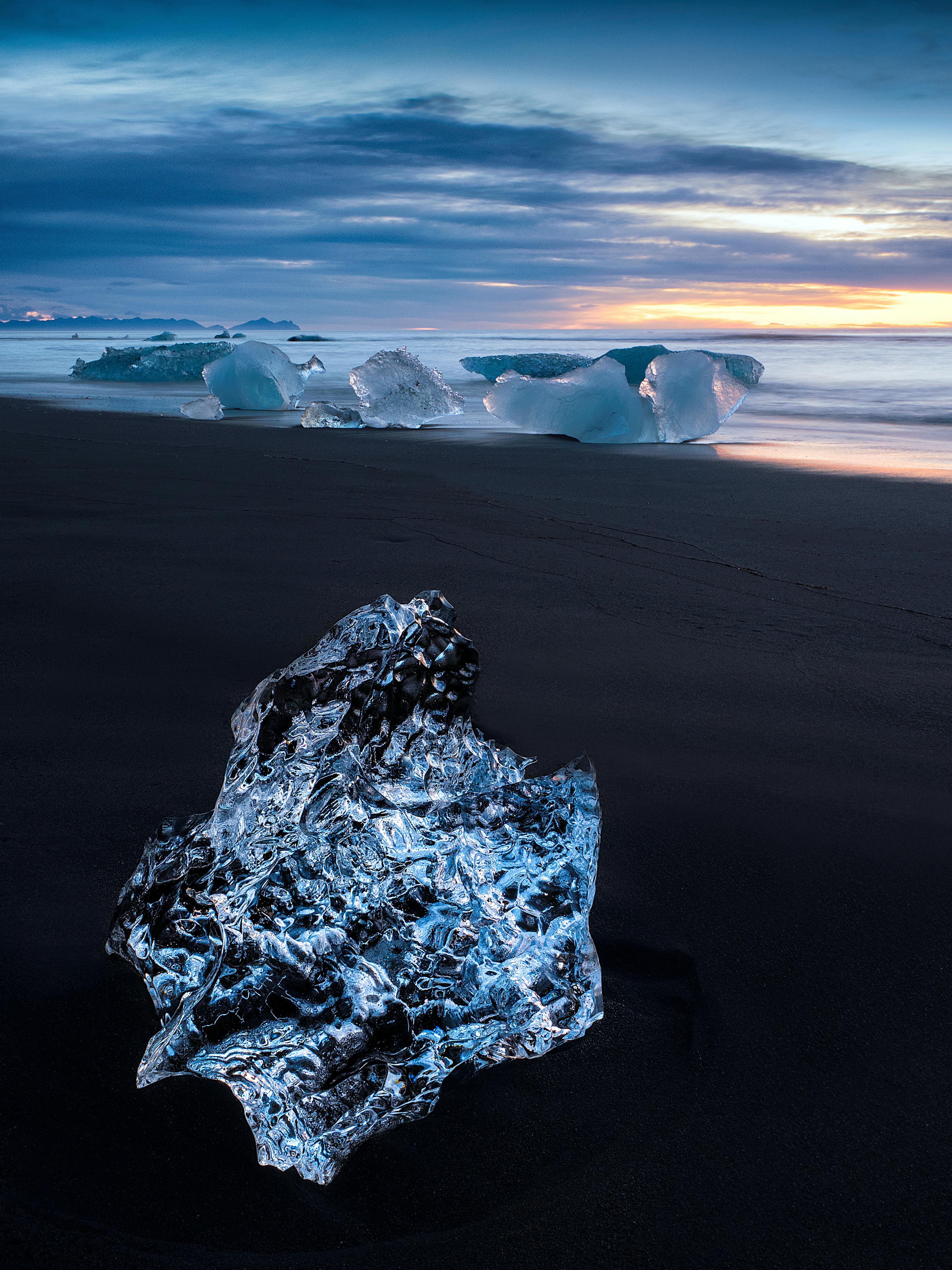 A crystal clear iceberg washed up on the black volcanic sands of the ...