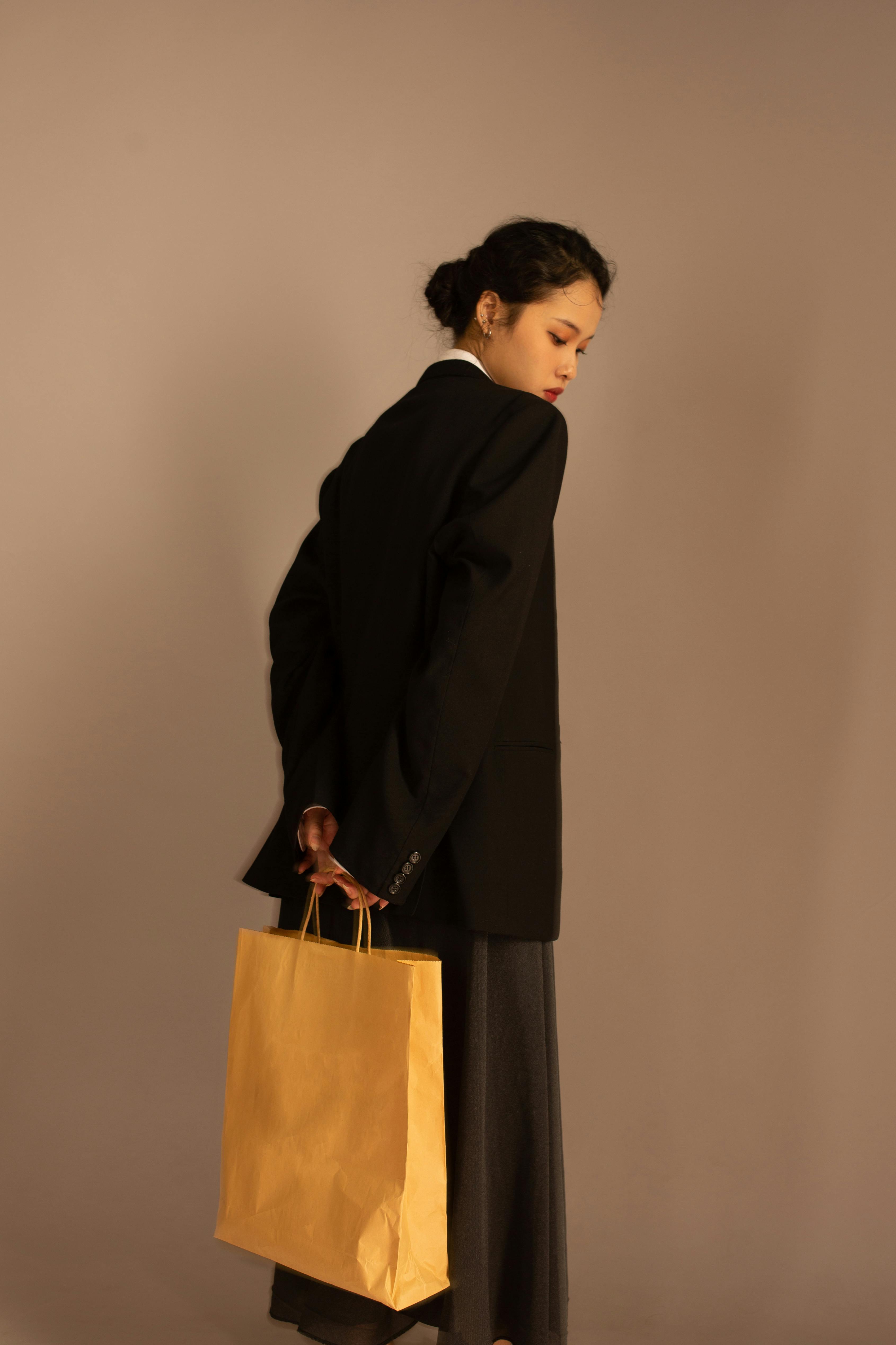 Fashionable Woman Holding a Paper Bag behind Her Back · Free Stock Photo