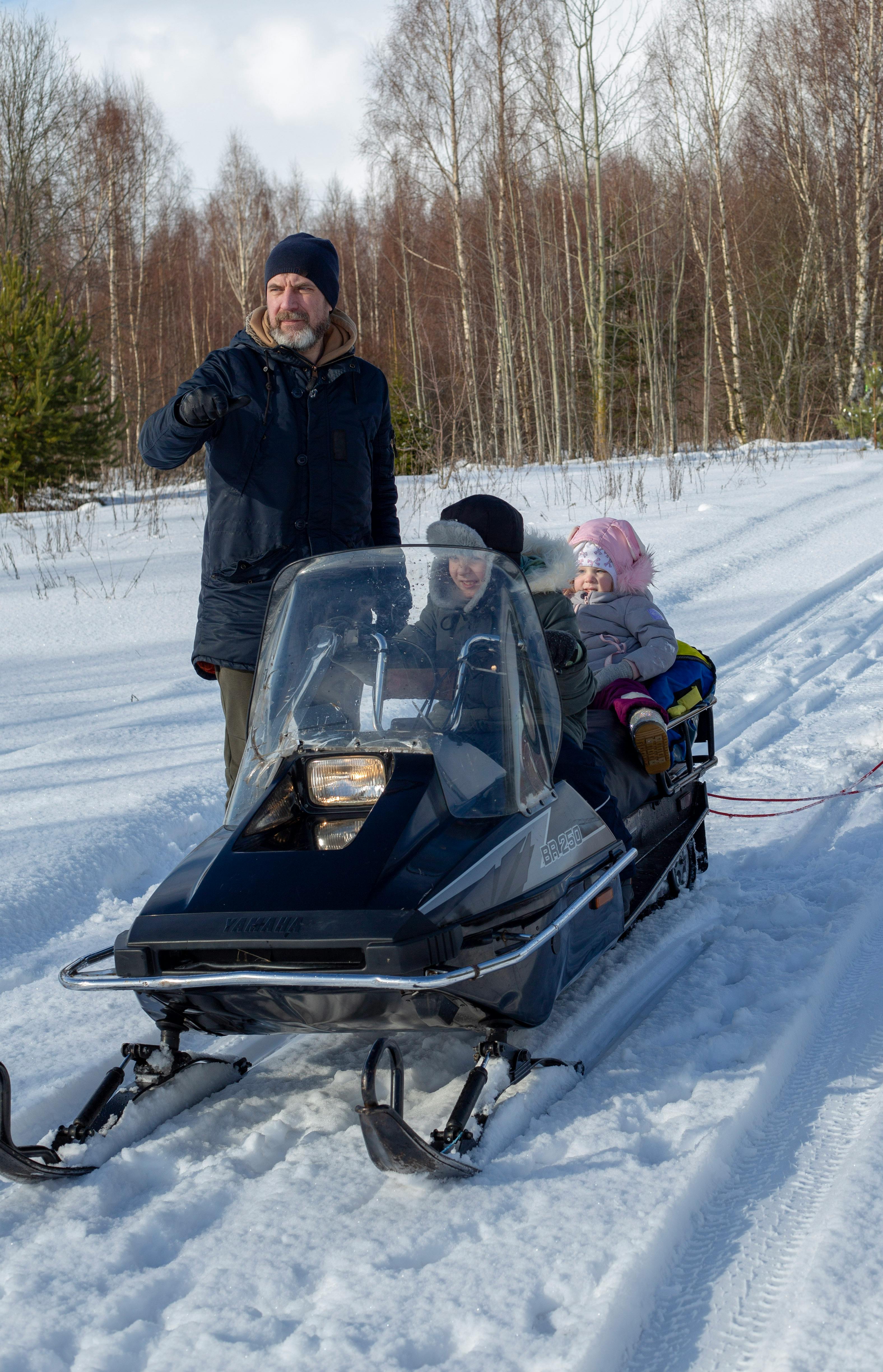 Father Standing by Kids Sitting on Snowmobile · Free Stock Photo