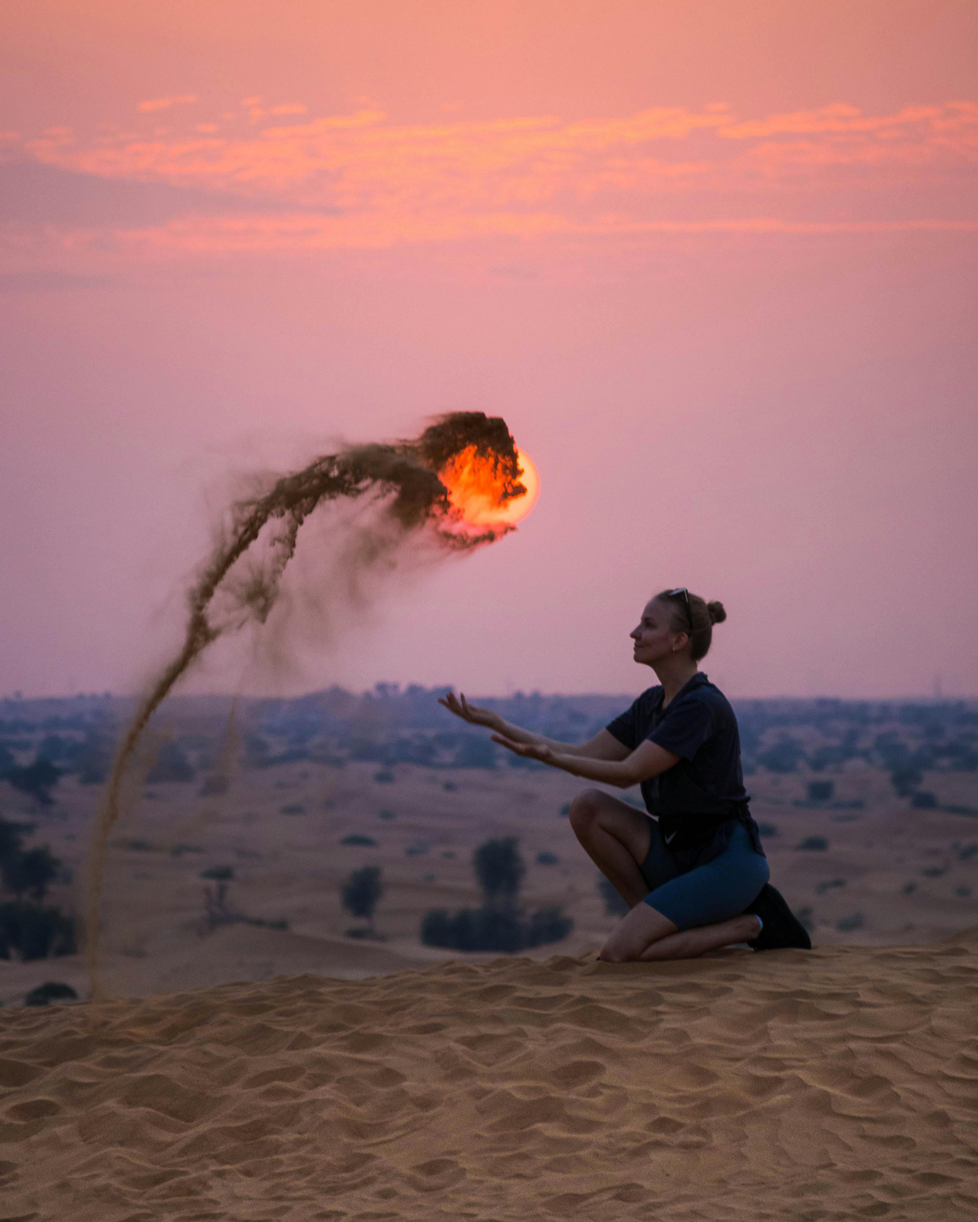 Woman Crouching on Sand and Throwing Sand at Dusk · Free Stock Photo
