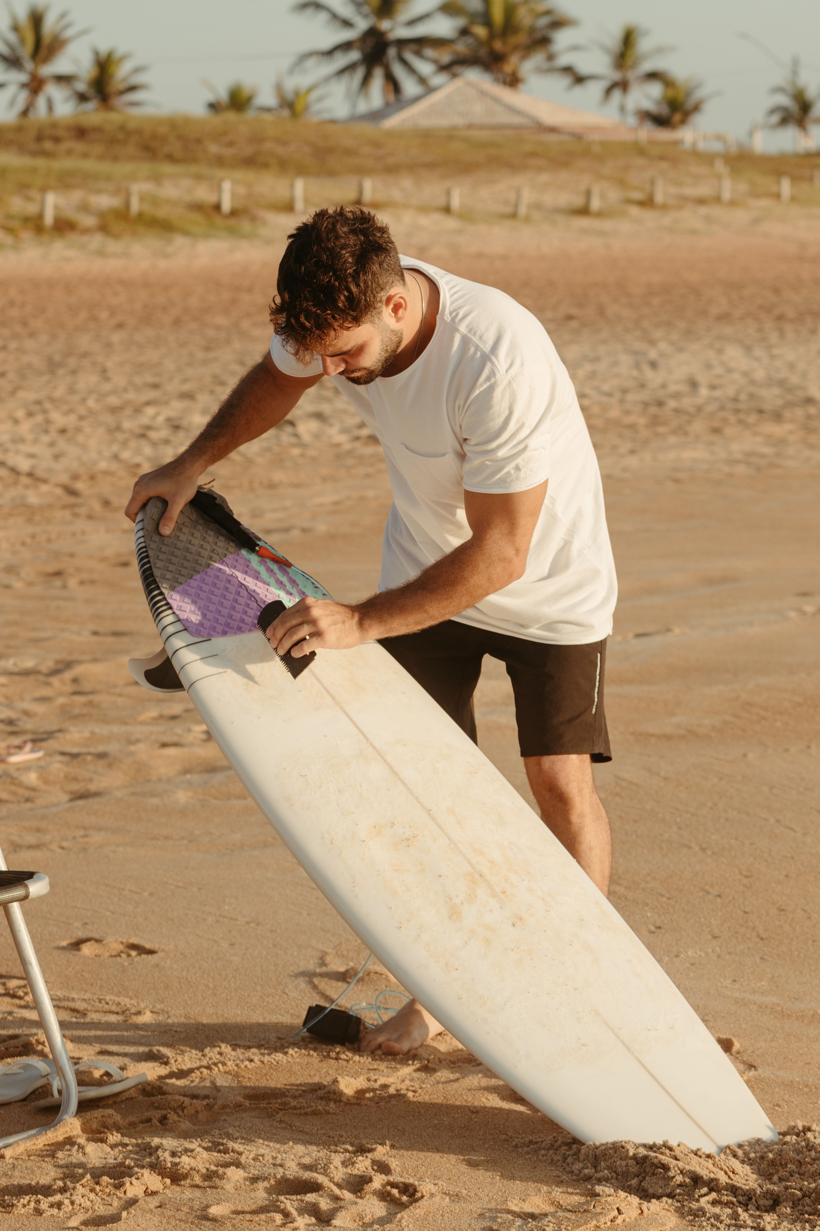 Man Sanding his Surfboard on Beach · Free Stock Photo