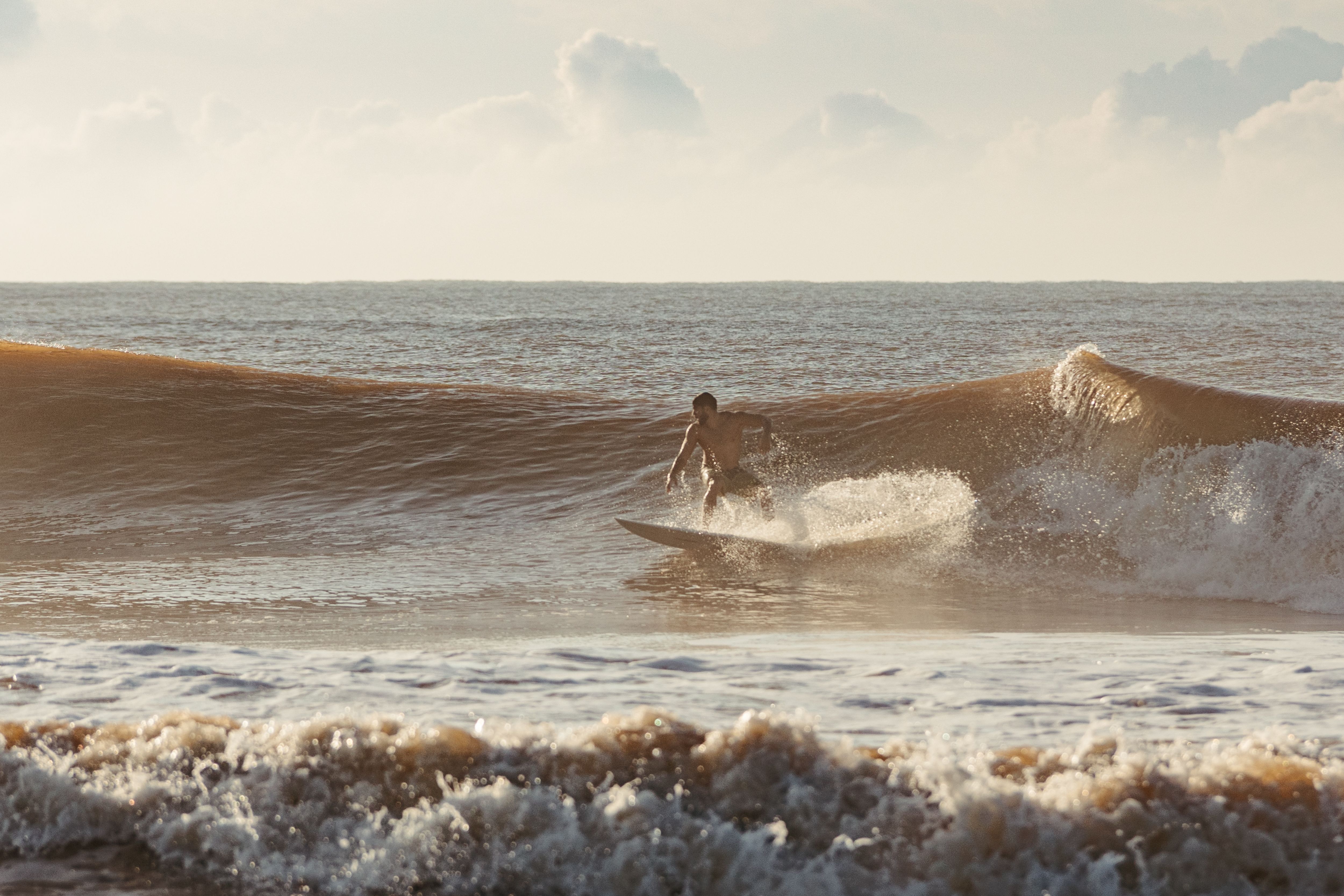 Man Surfing on Waves by Sea Shore under Clear Sky · Free Stock Photo