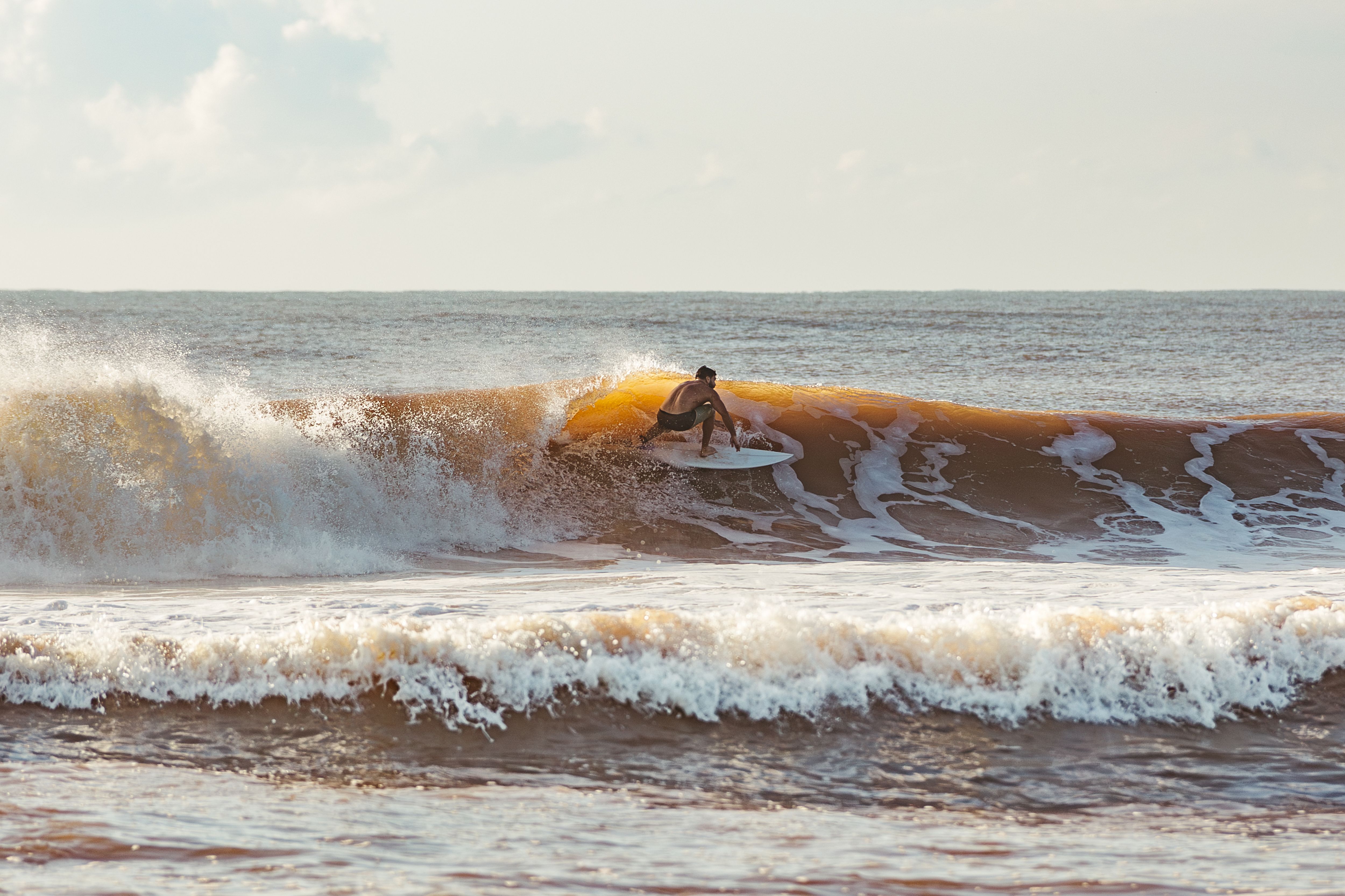 Man Surfing by Sea Shore under Clear Sky · Free Stock Photo