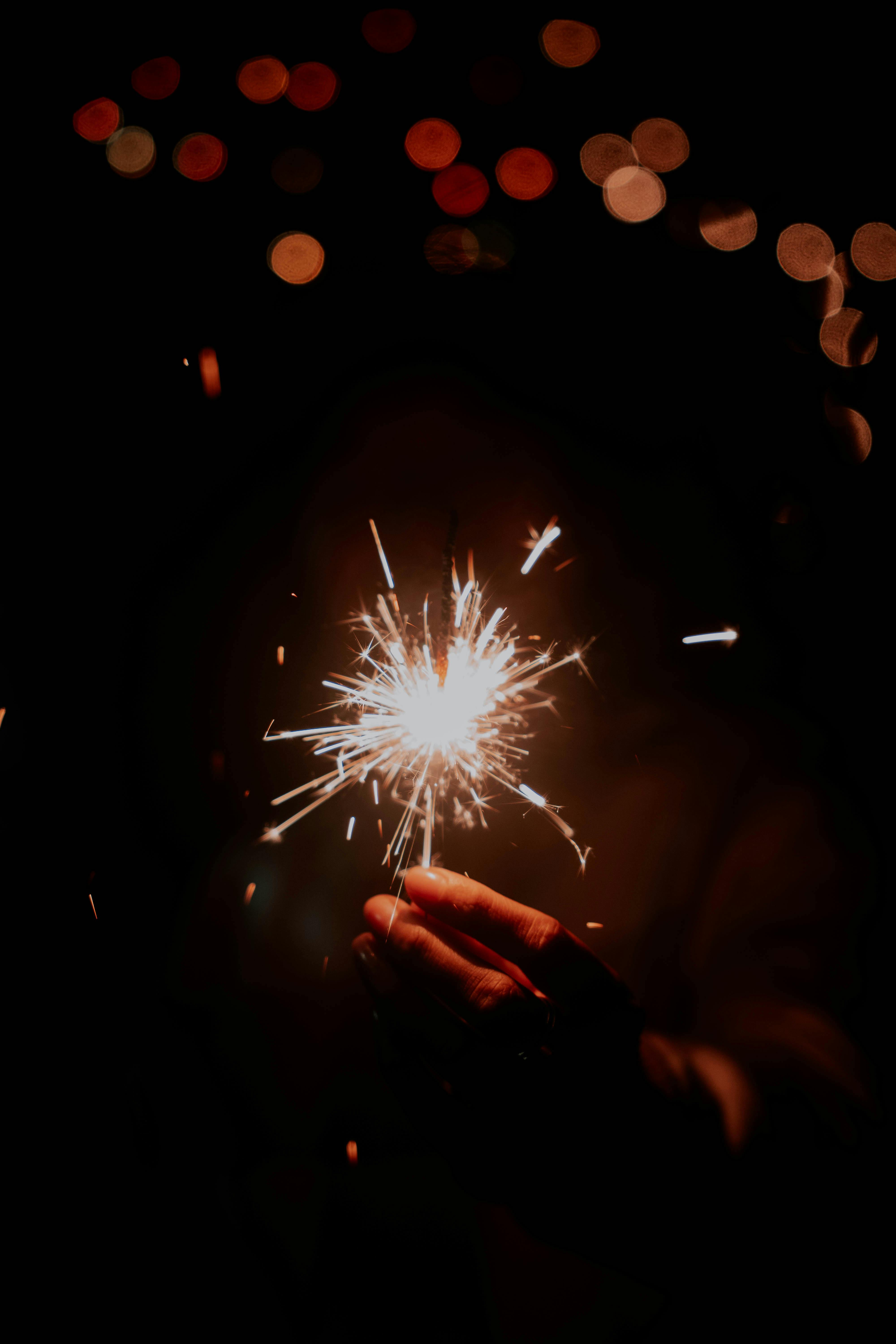 Man Holding Sparklers in the Dark · Free Stock Photo