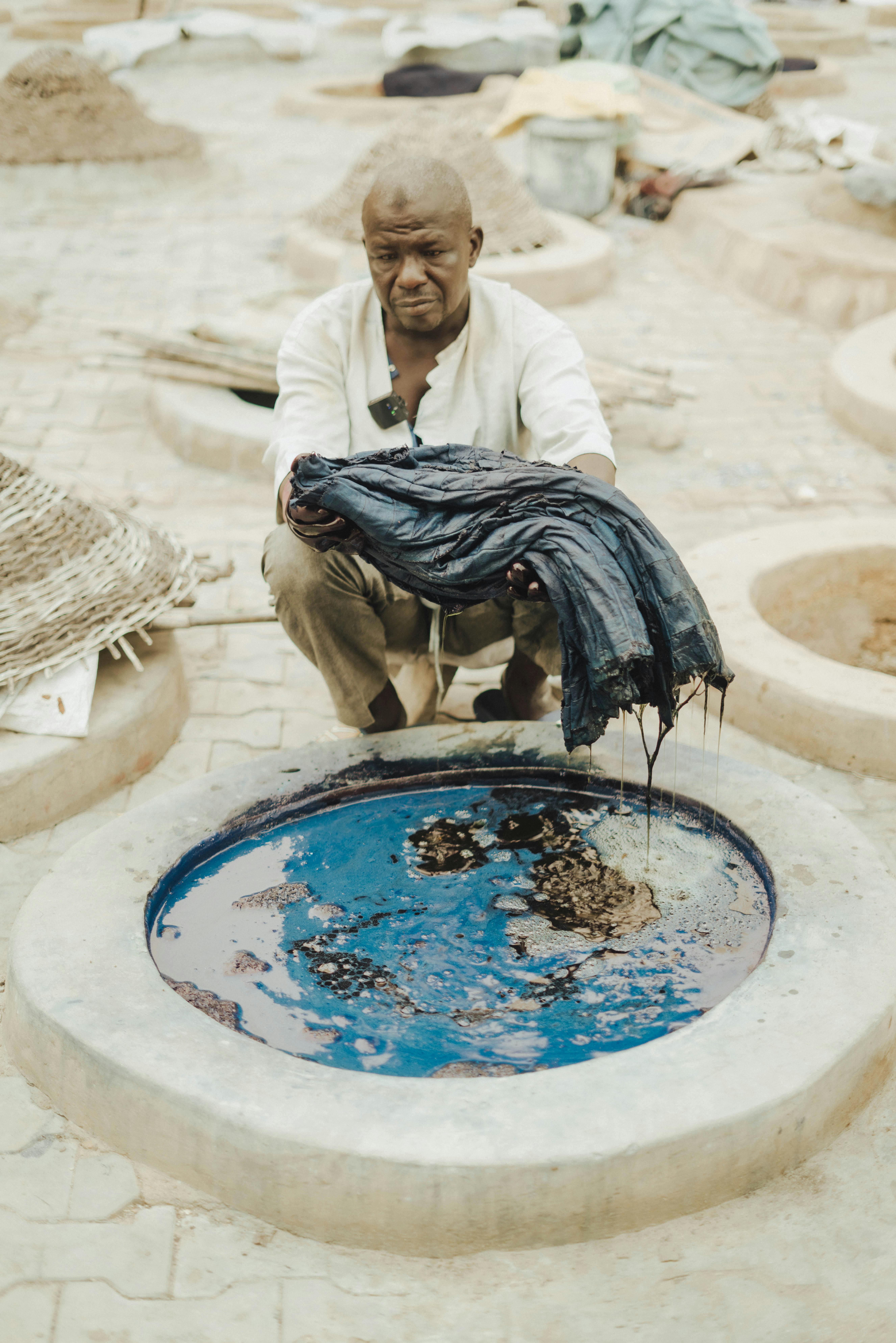 Man Dyeing Black Cloth in Pit · Free Stock Photo