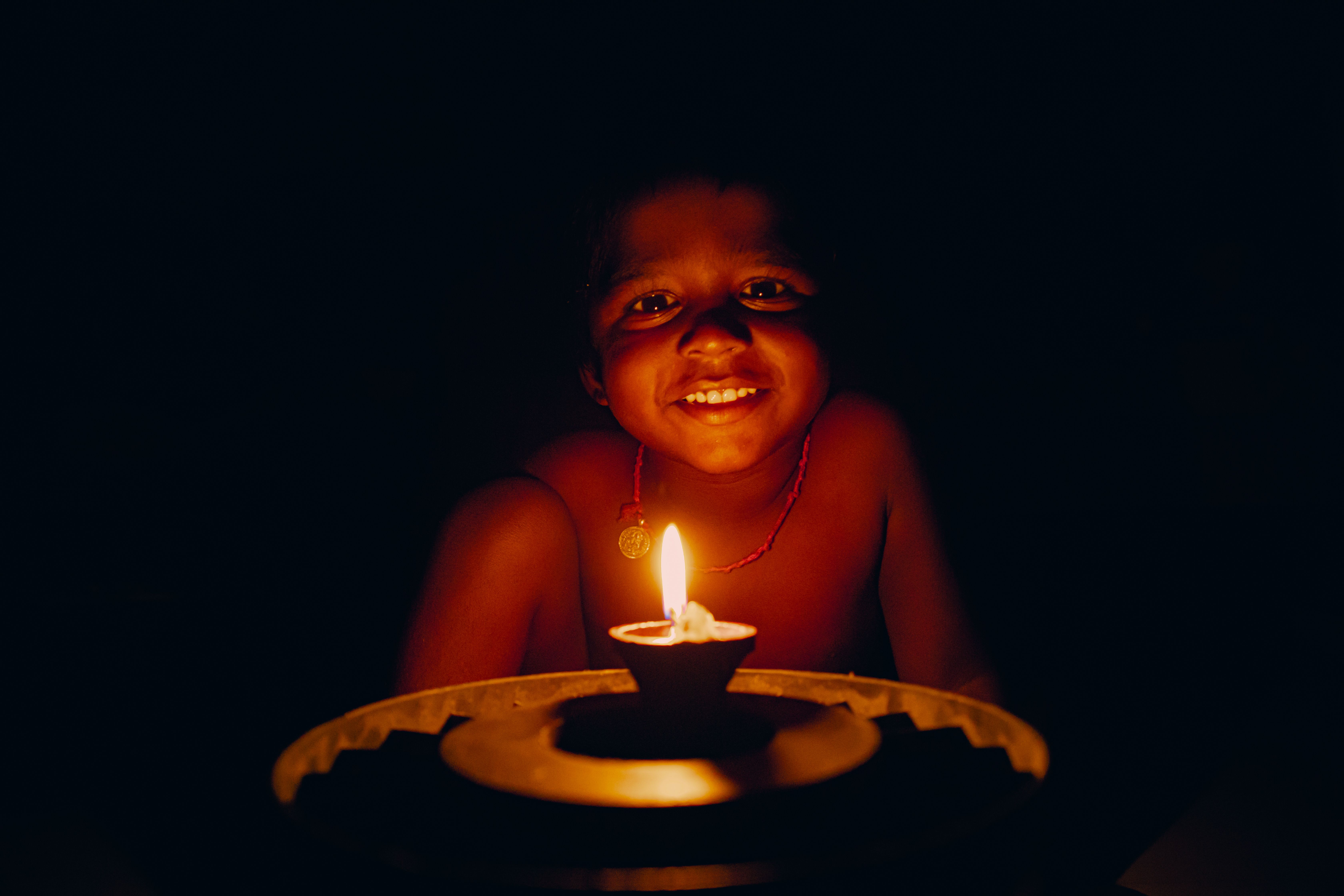 Smiling Child Sitting in the Candlelight · Free Stock Photo