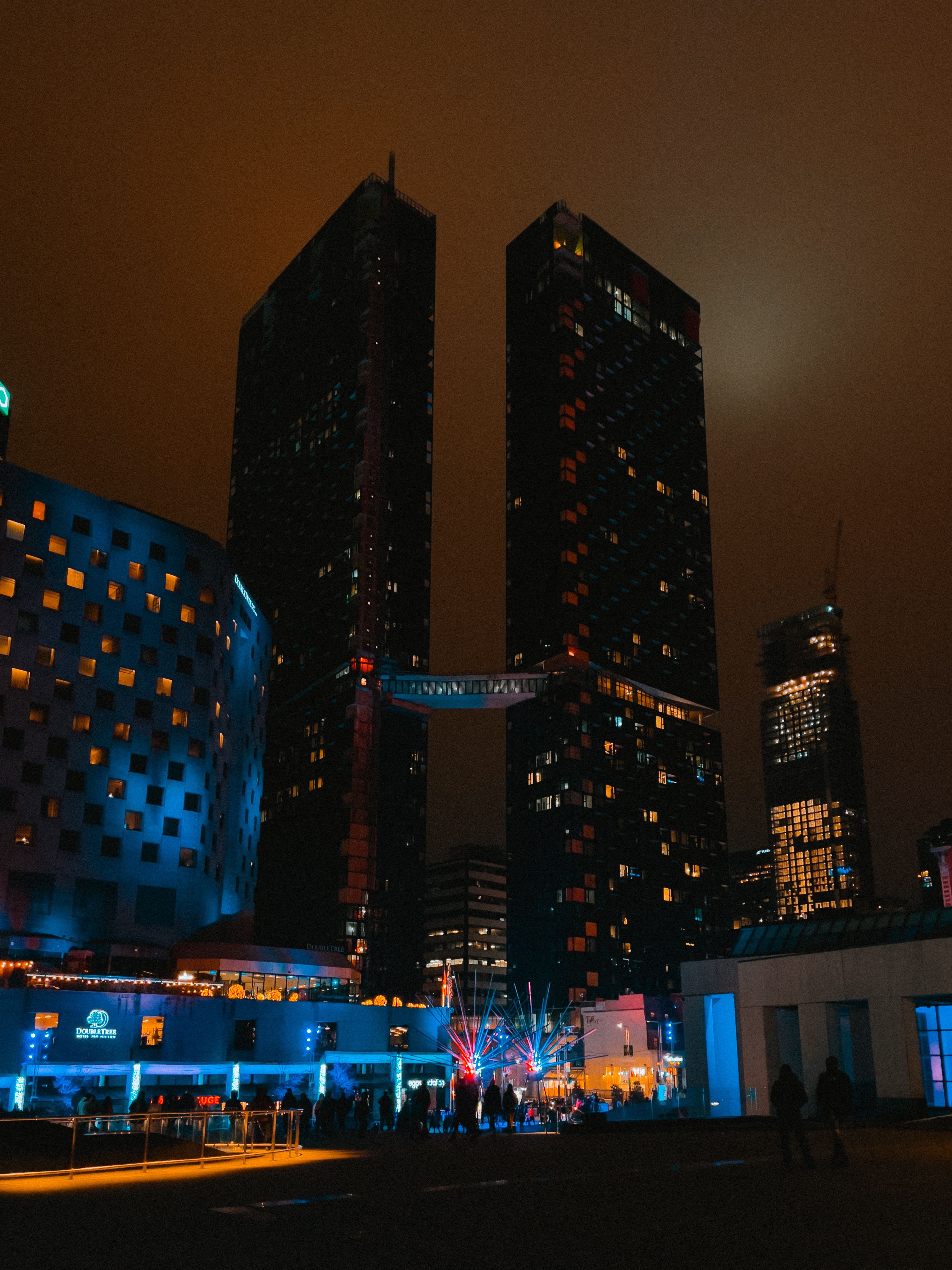 Twin Skyscrapers Connected by Skybridge at Night · Free Stock Photo
