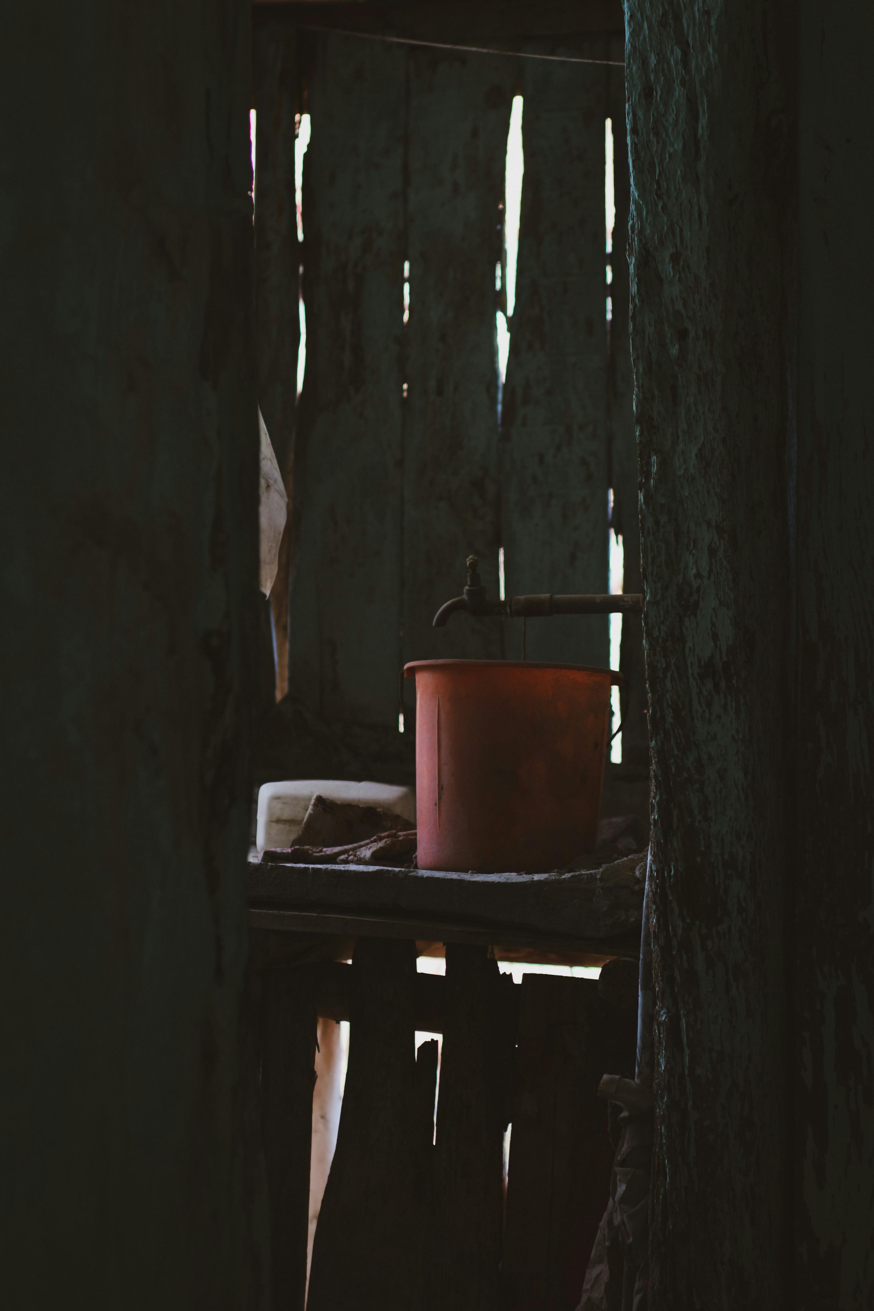Bucket Standing under a Rusty Faucet in a Wooden Hut · Free Stock Photo
