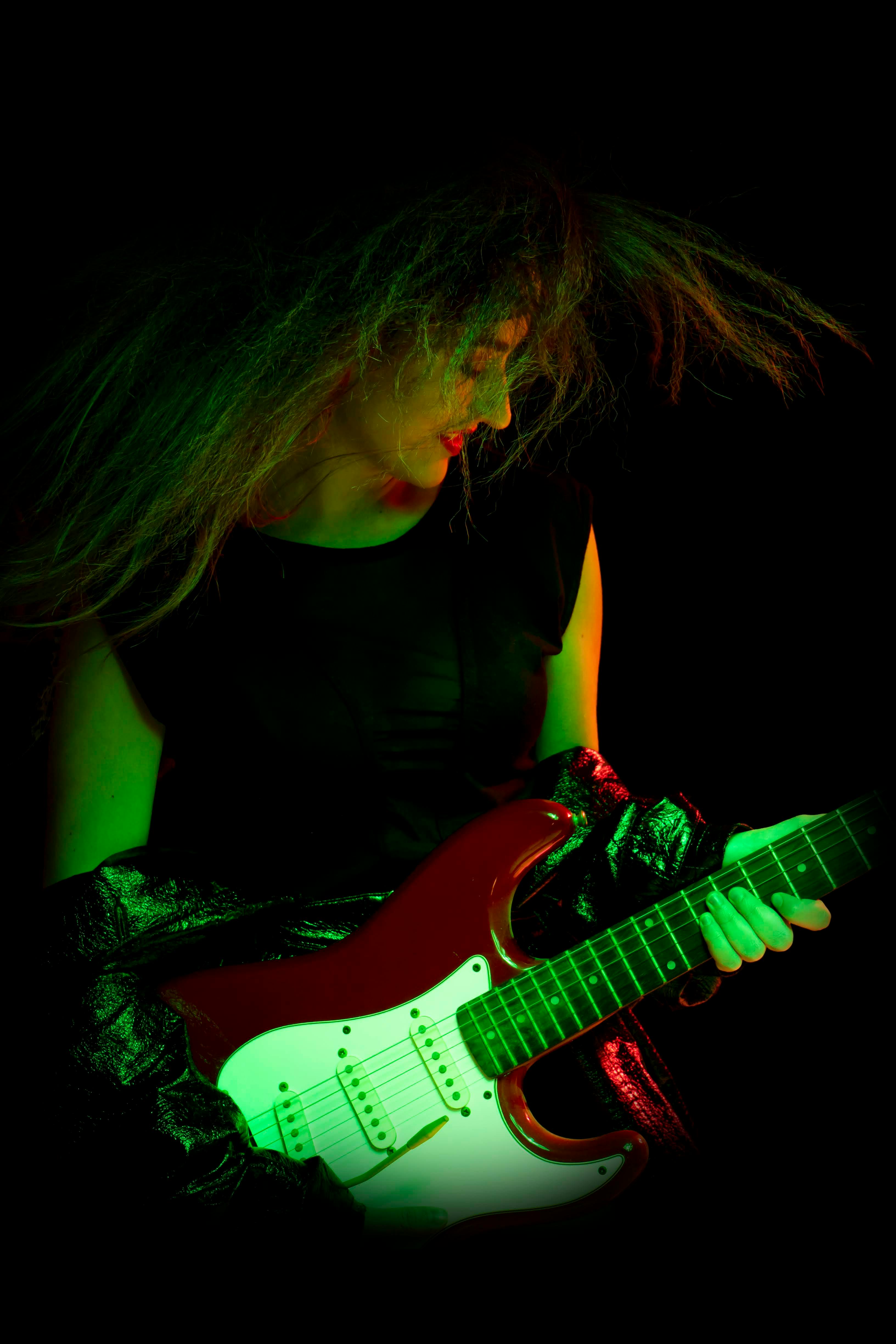 A woman with long hair playing an electric guitar · Free Stock Photo