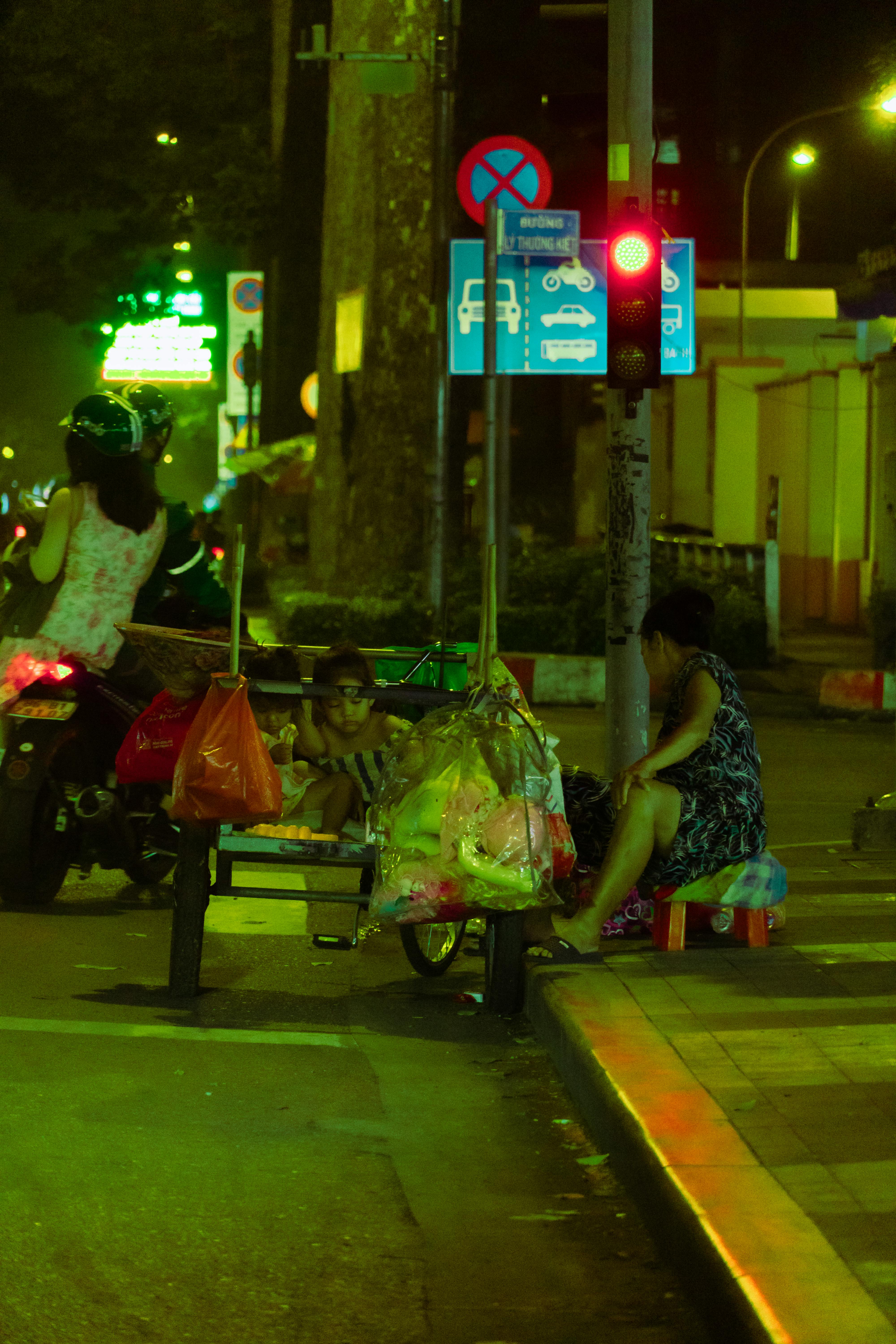 Children Sitting in a Cart Standing by the Curb at Night · Free Stock Photo