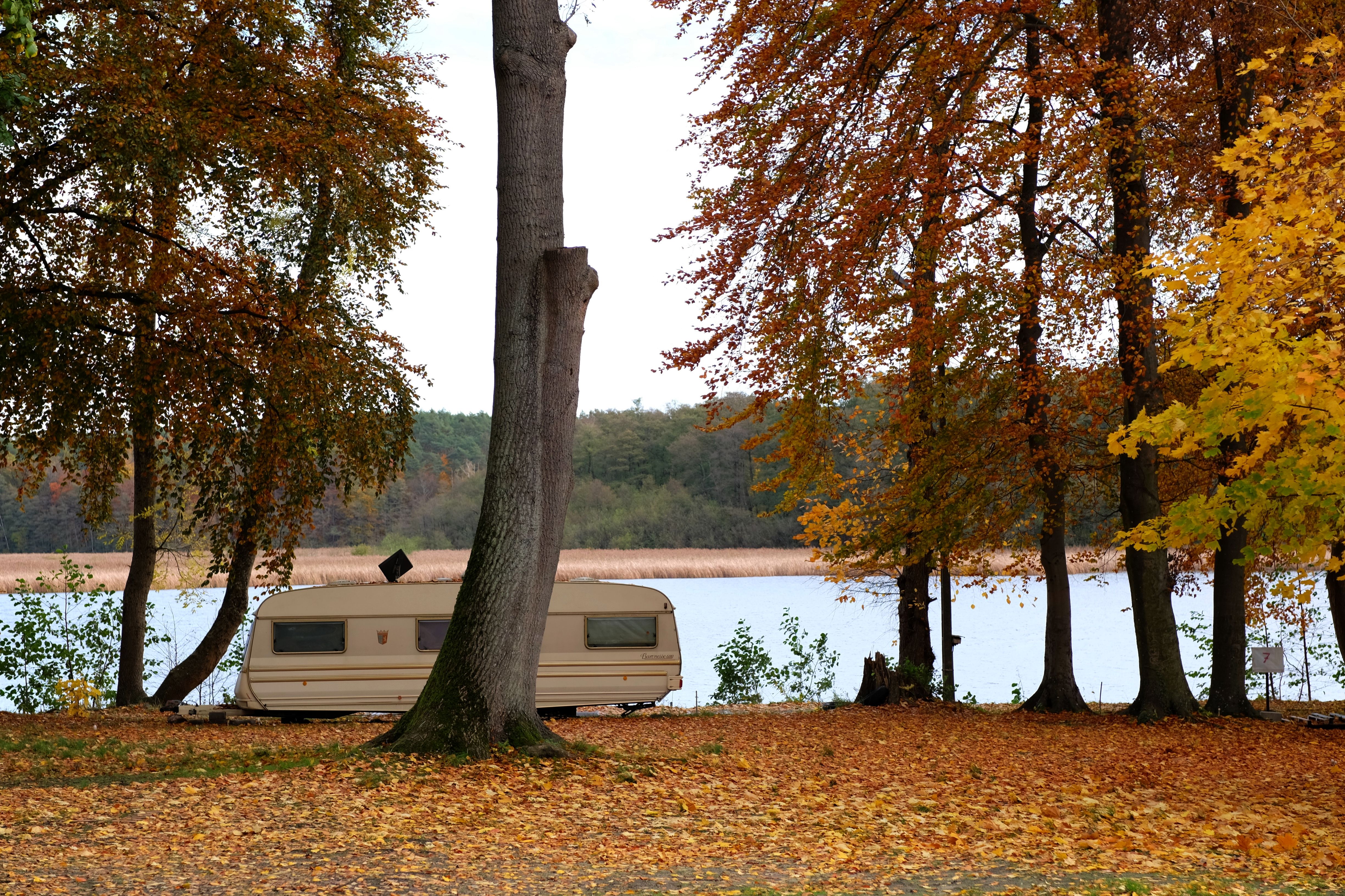 A Camper Trailer Parked Near A Lake With Trees Free Stock Photo