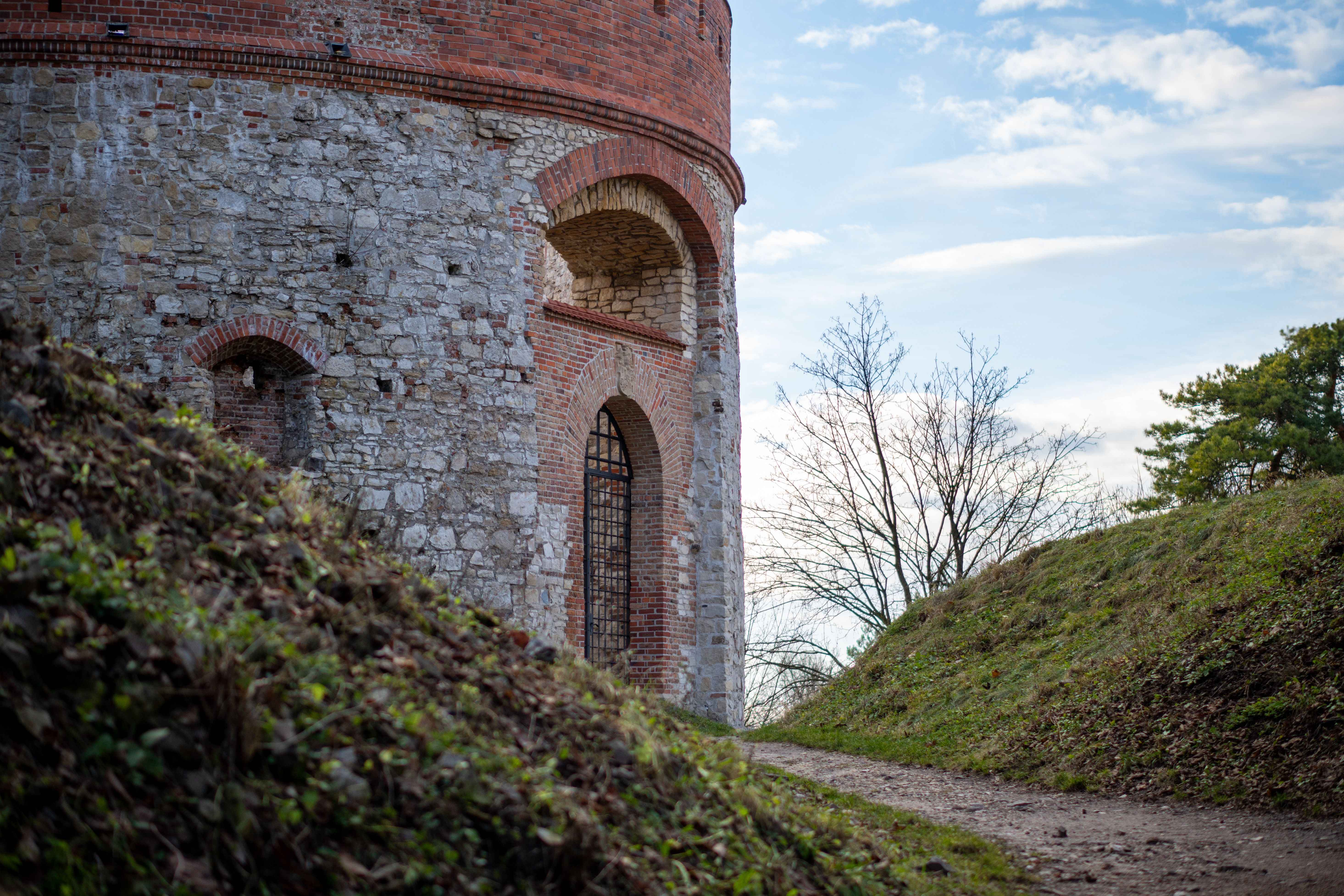 A man walking down a path next to a brick building · Free Stock Photo
