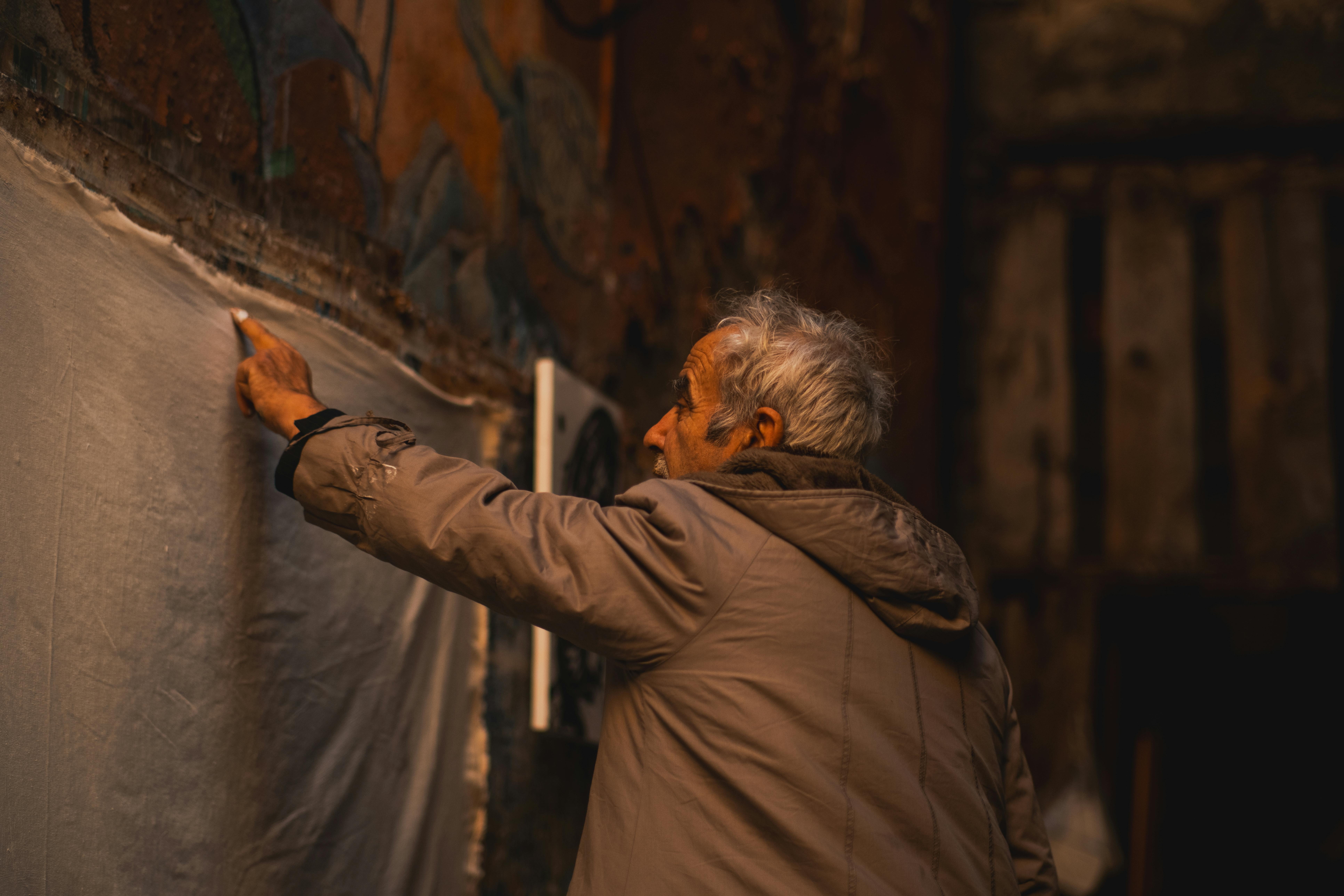 Grey Haired Man Pointing at a White Sheet · Free Stock Photo