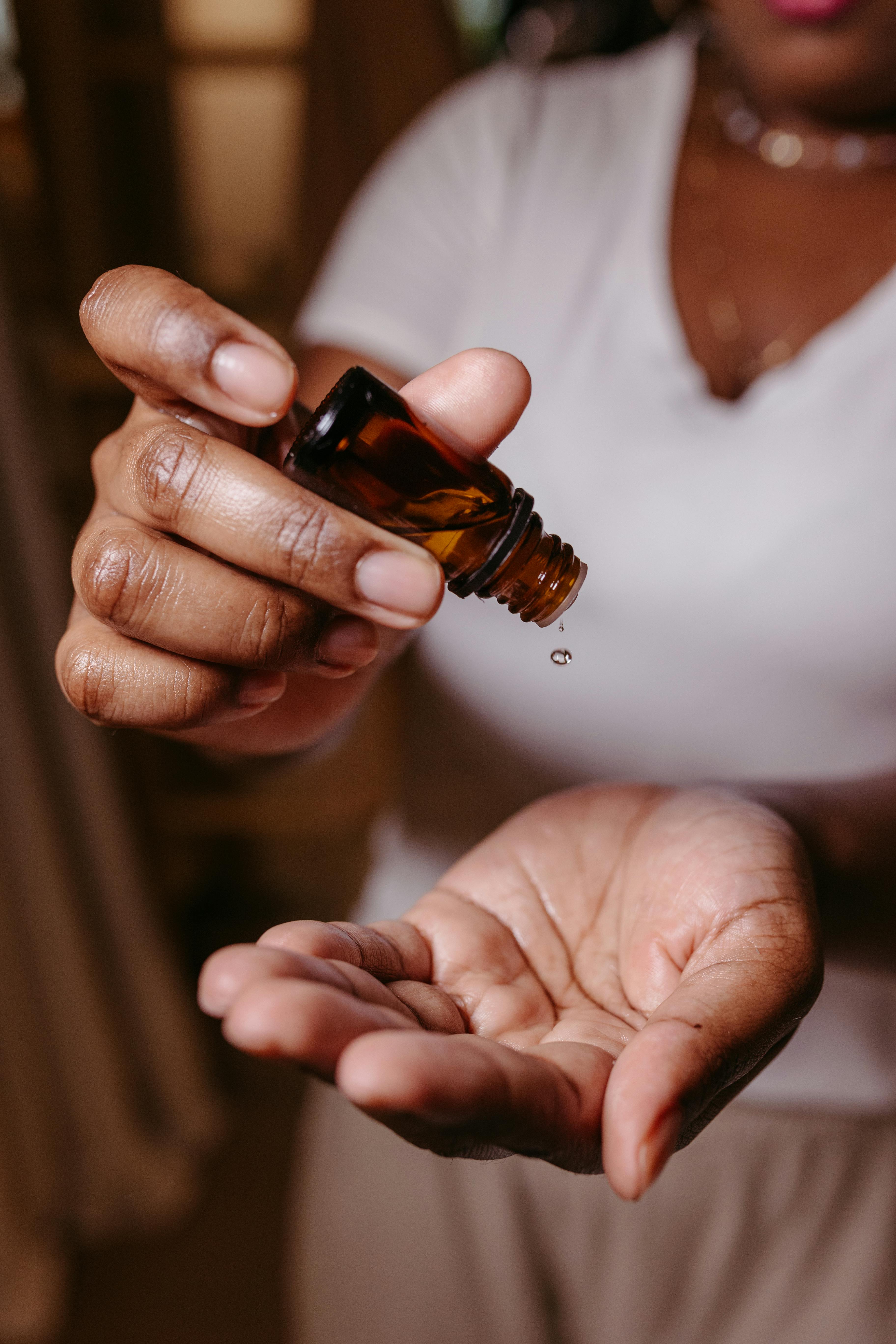 Dripping the Oil From the Vial into Hand · Free Stock Photo