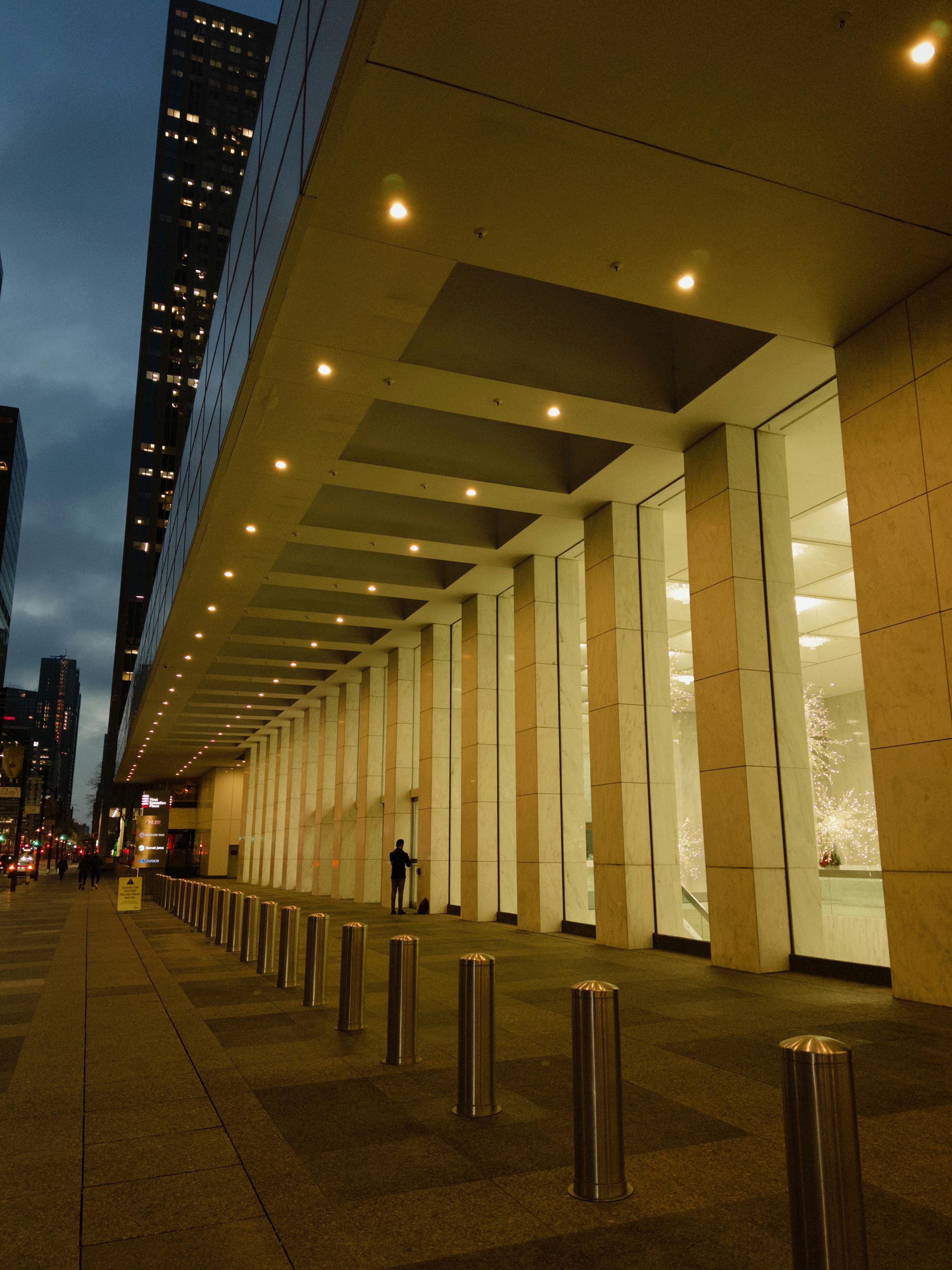 The building is lit up at night with tall columns · Free Stock Photo