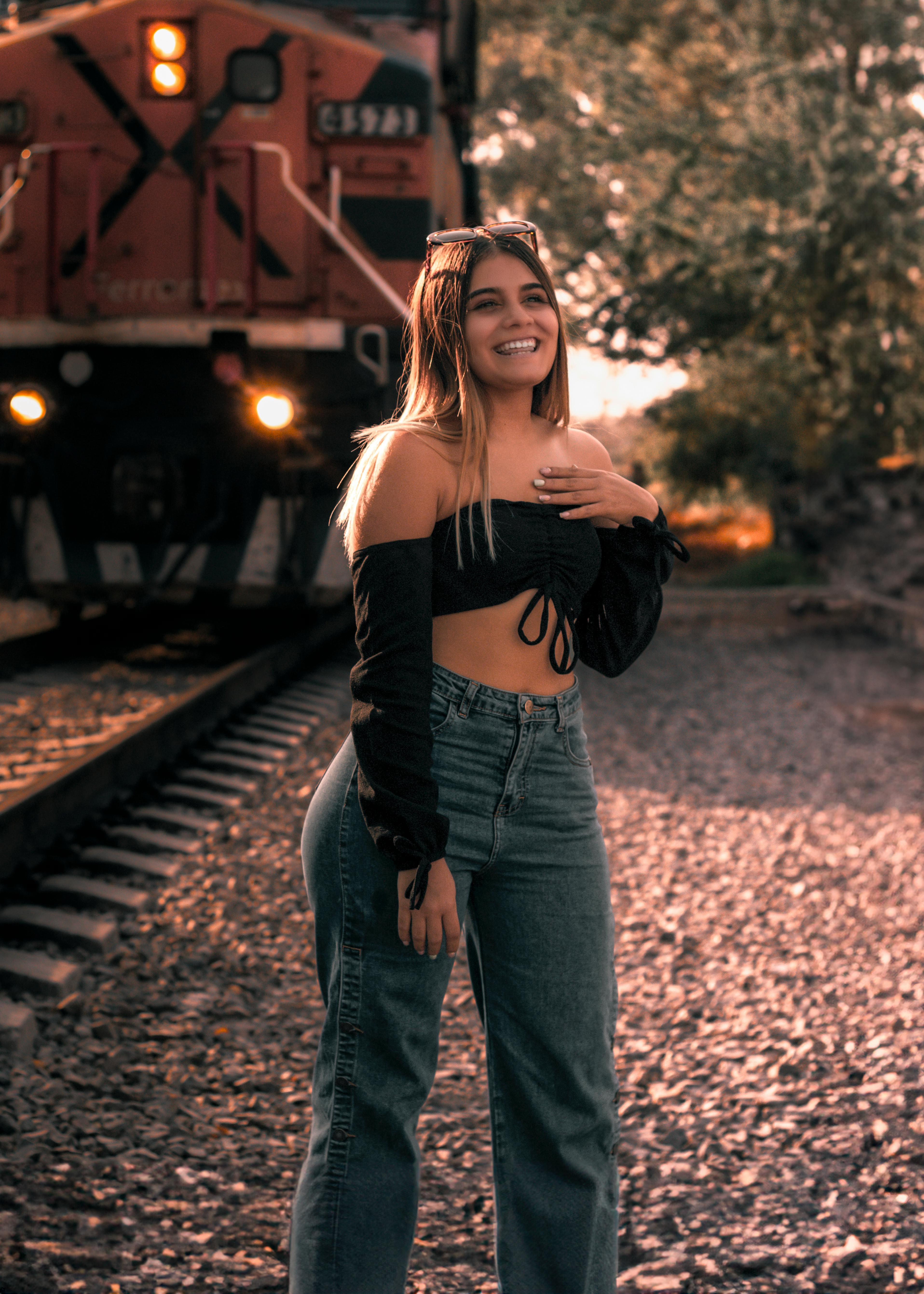 Smiling Woman in Bra and Jeans Standing by Railway · Free Stock Photo