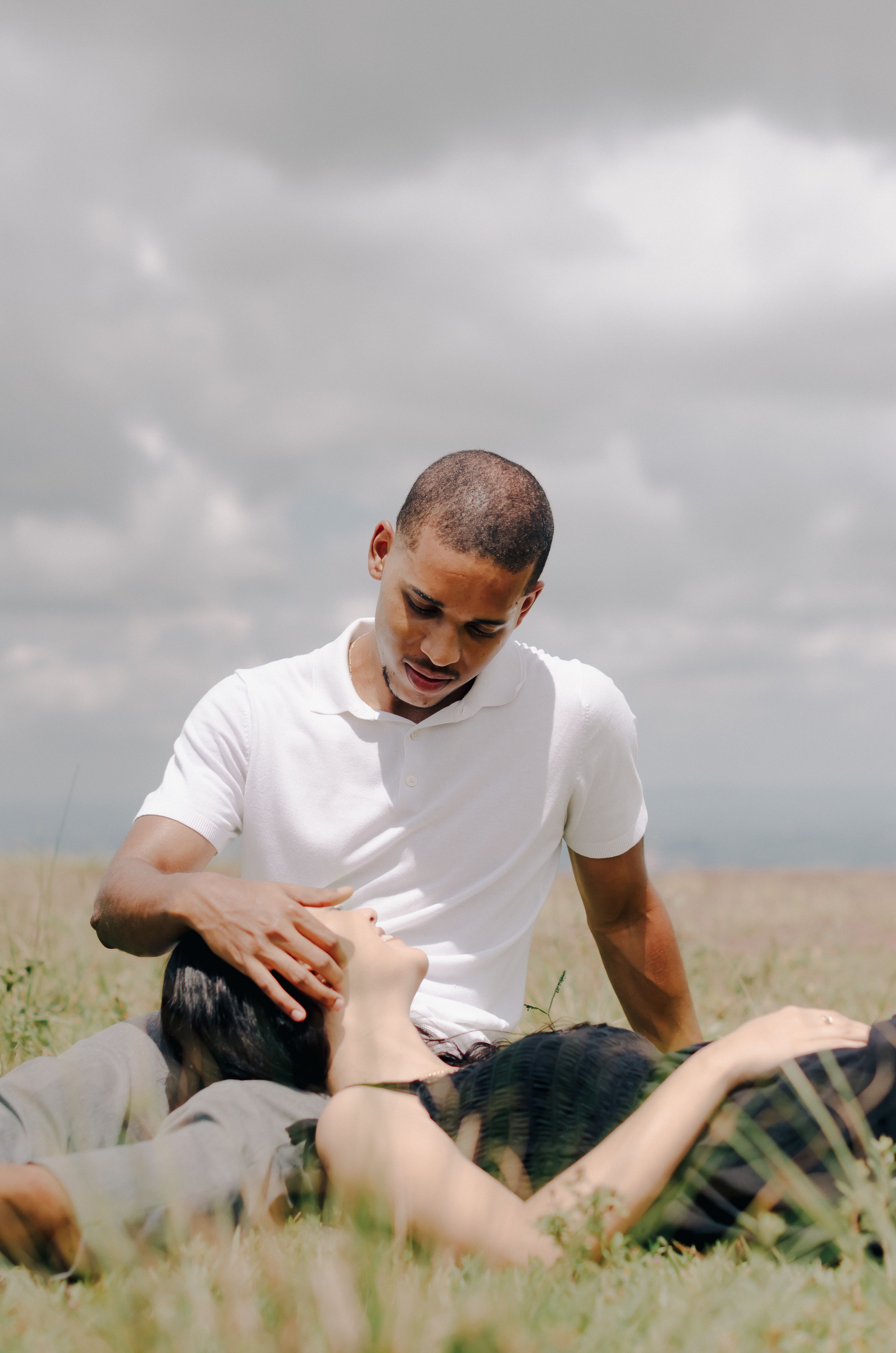 Man Sitting on the Grass and Looking at his Girlfriend Lying on his Lap ...