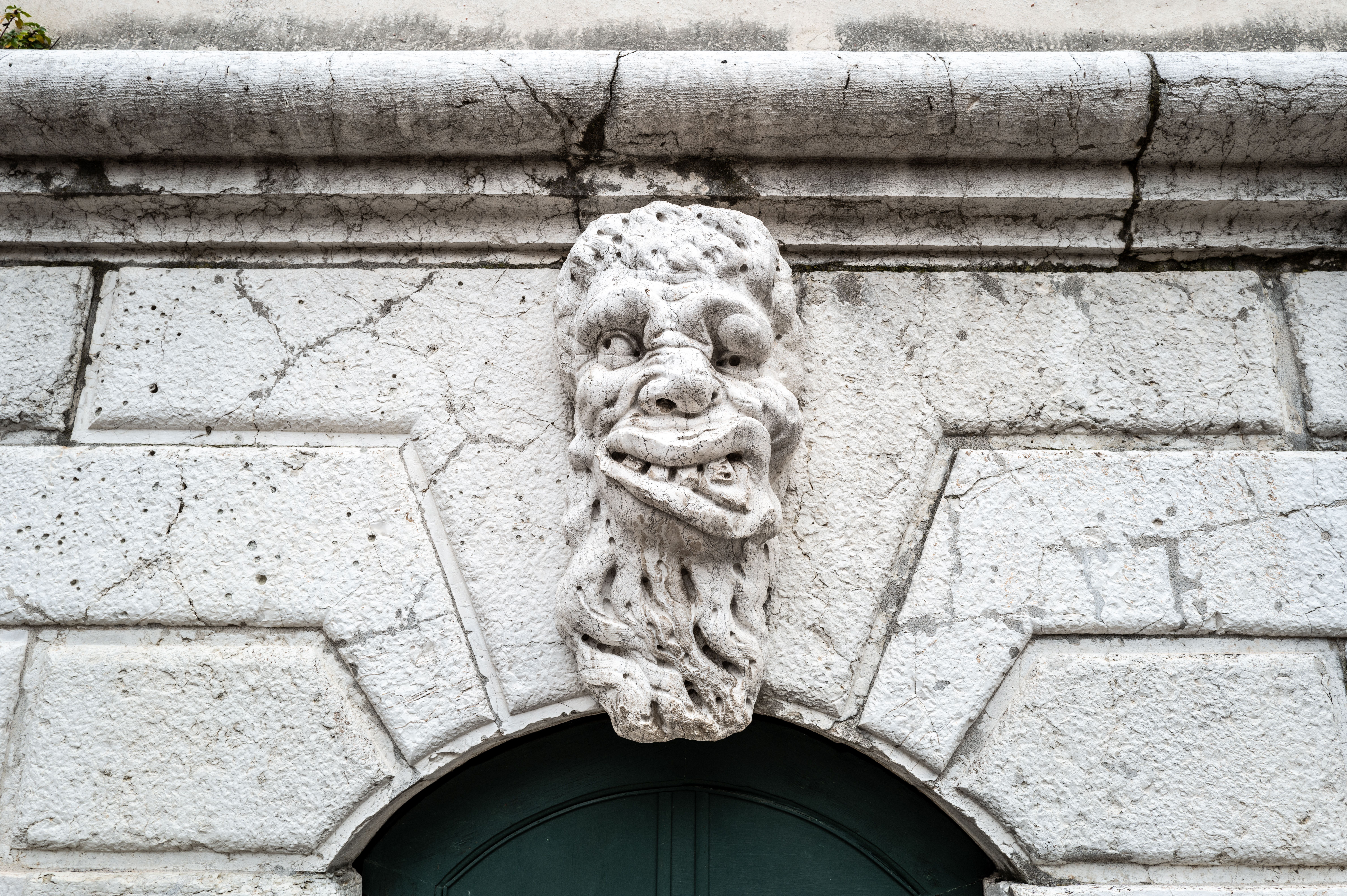 A stone head on the side of a building · Free Stock Photo