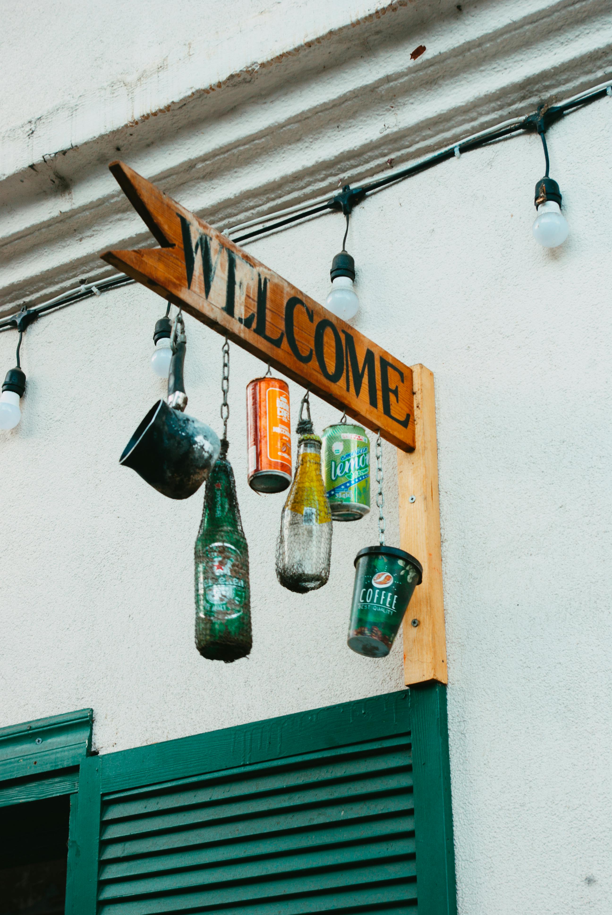 Welcome Sign With Bottles and Cups Hanging · Free Stock Photo